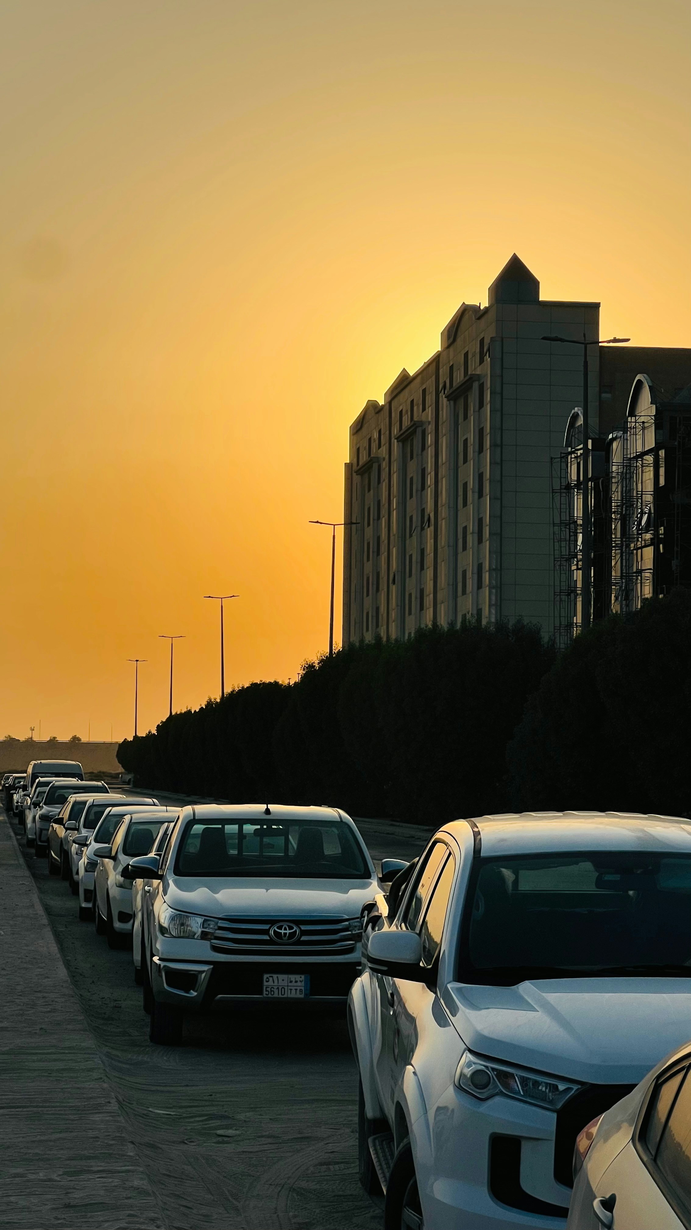 Golden Hour Silhouette: A Dusk-lit Hotel Over a Line of Parked Cars