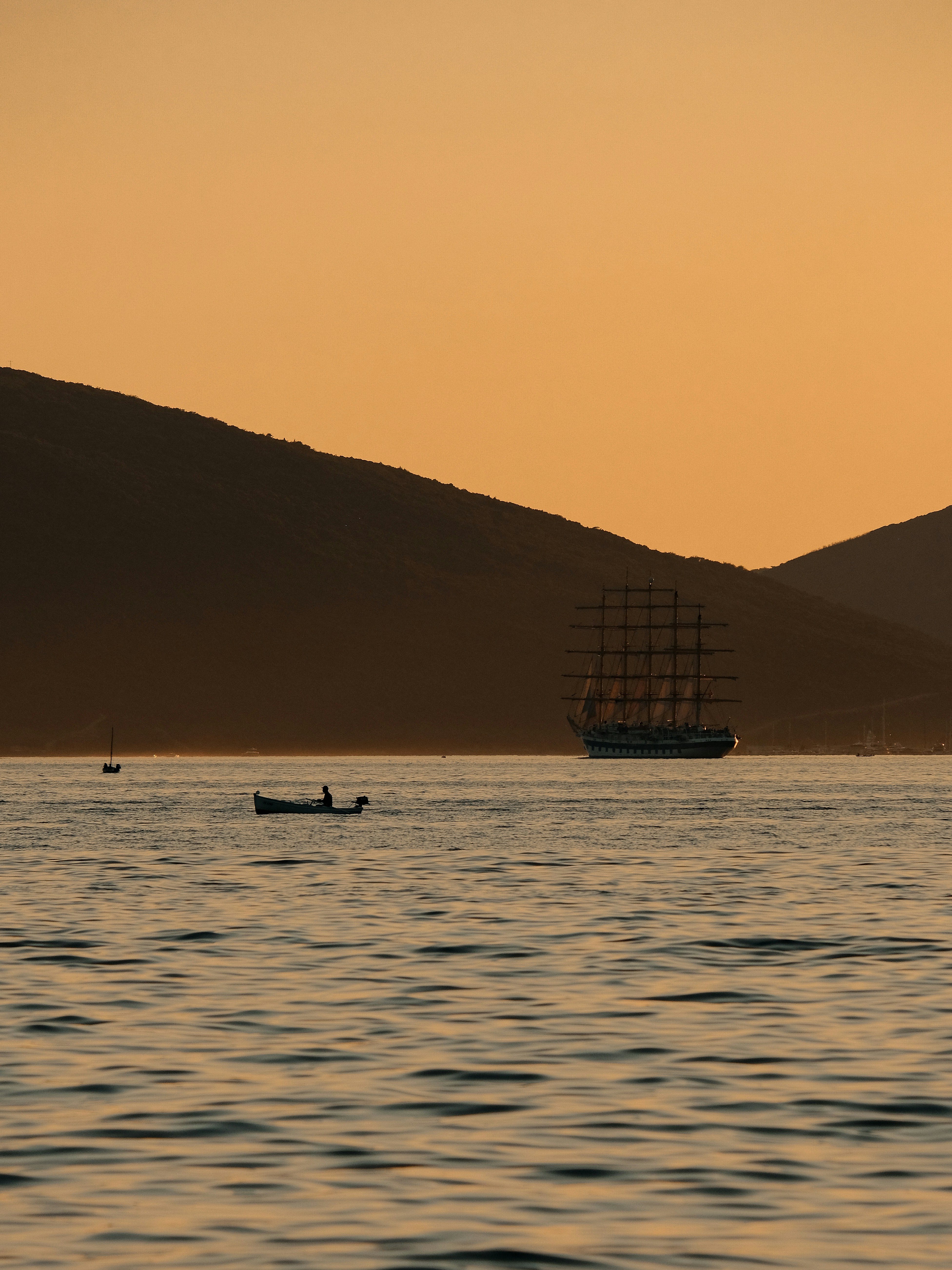 Sailing ship and small boat on the water at sunset.