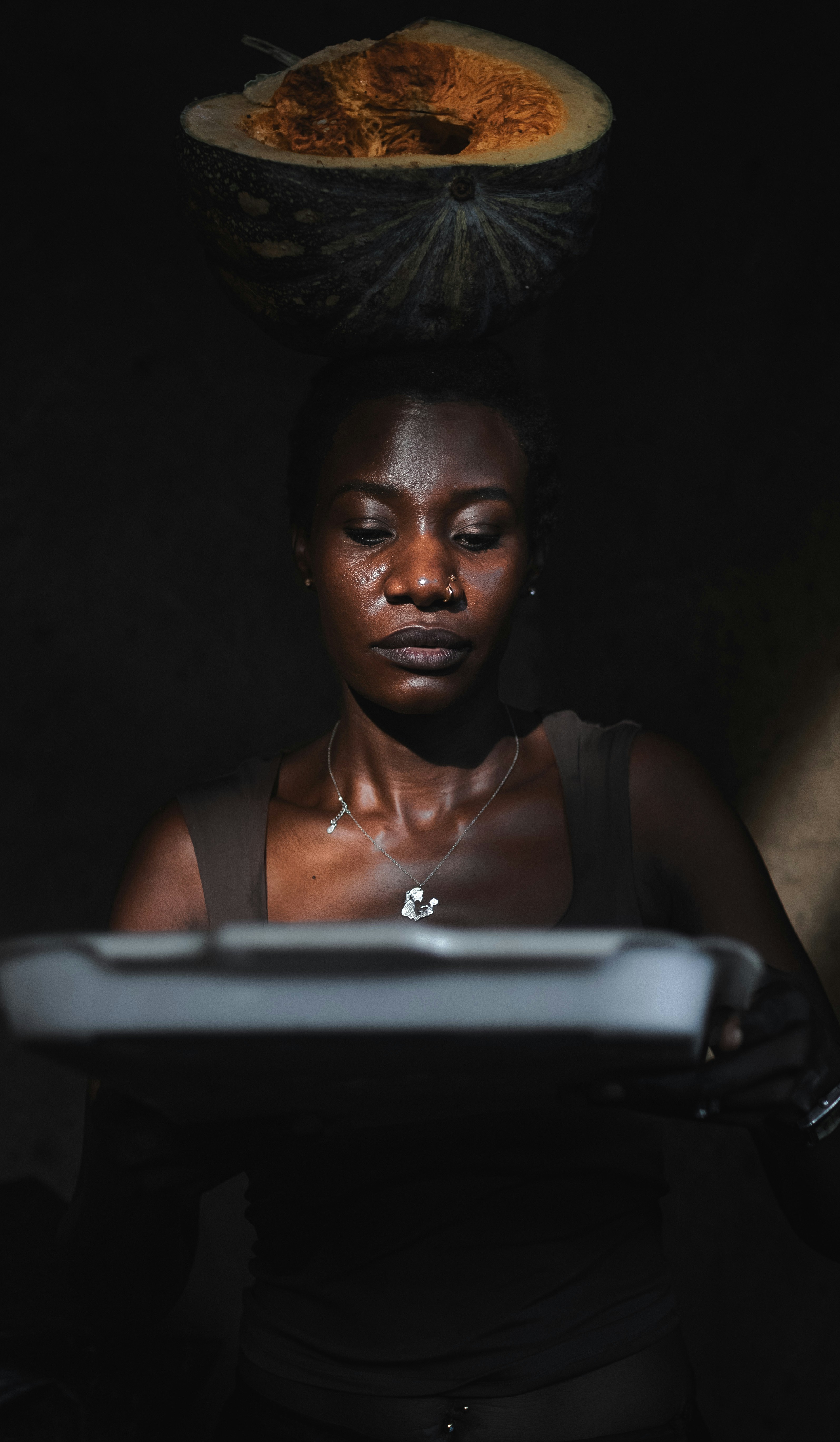 Portrait of an African woman | Woman balances cut pumpkin on head, holds tray