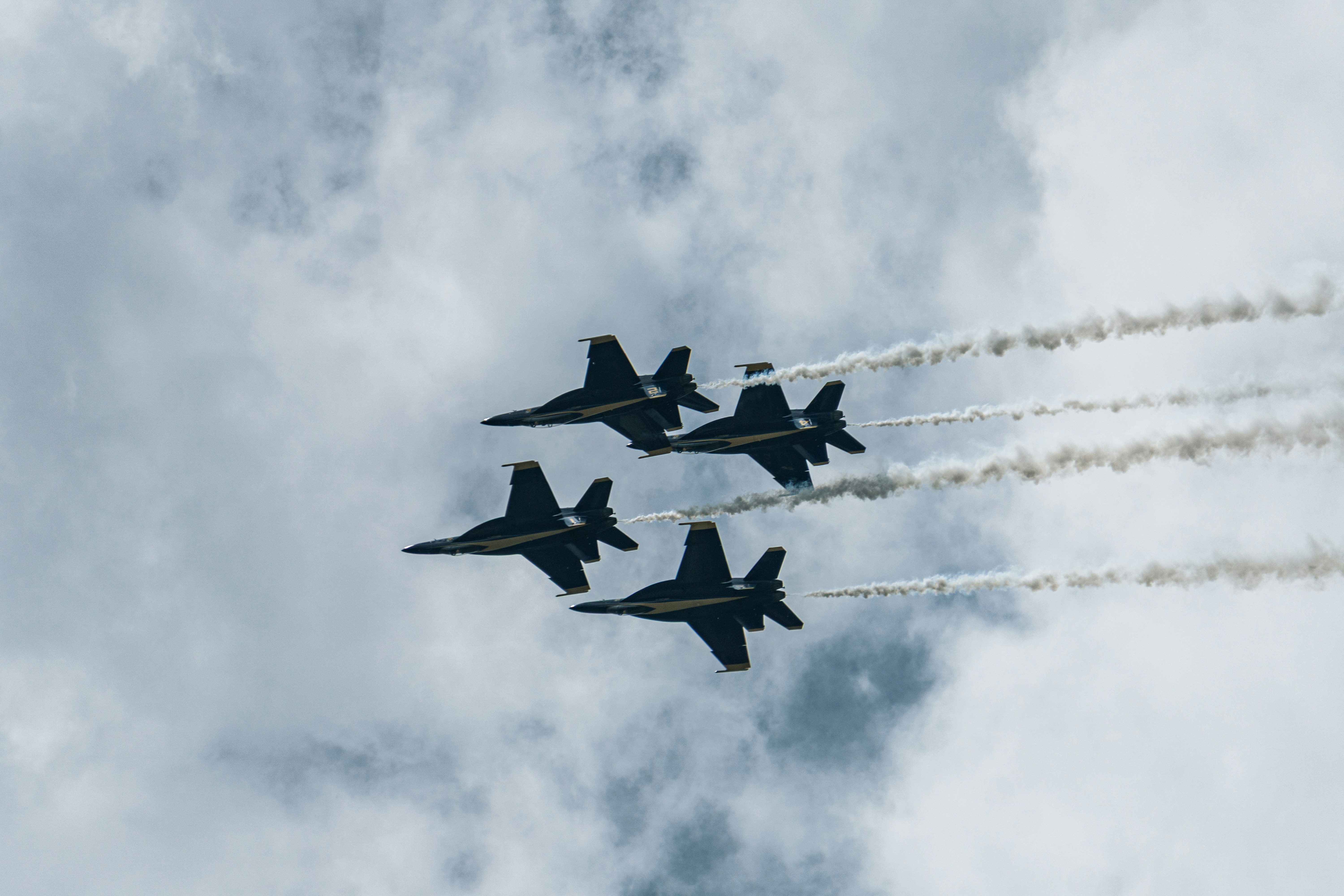 Four fighter jets flying in formation with smoke trails.