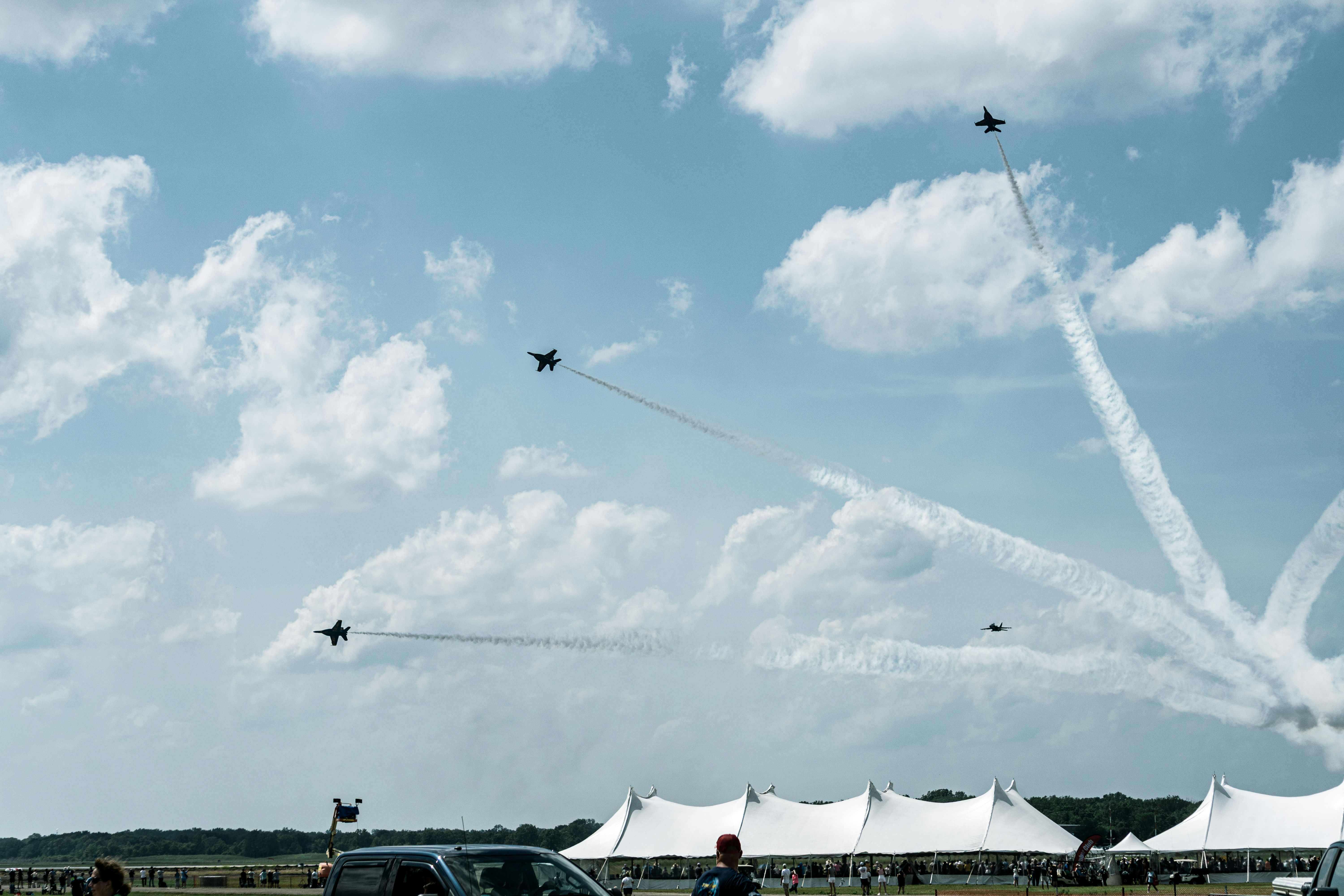 Jet Trails Over a Tent-Lined Field: An Aerial Show Across a Blue Sky