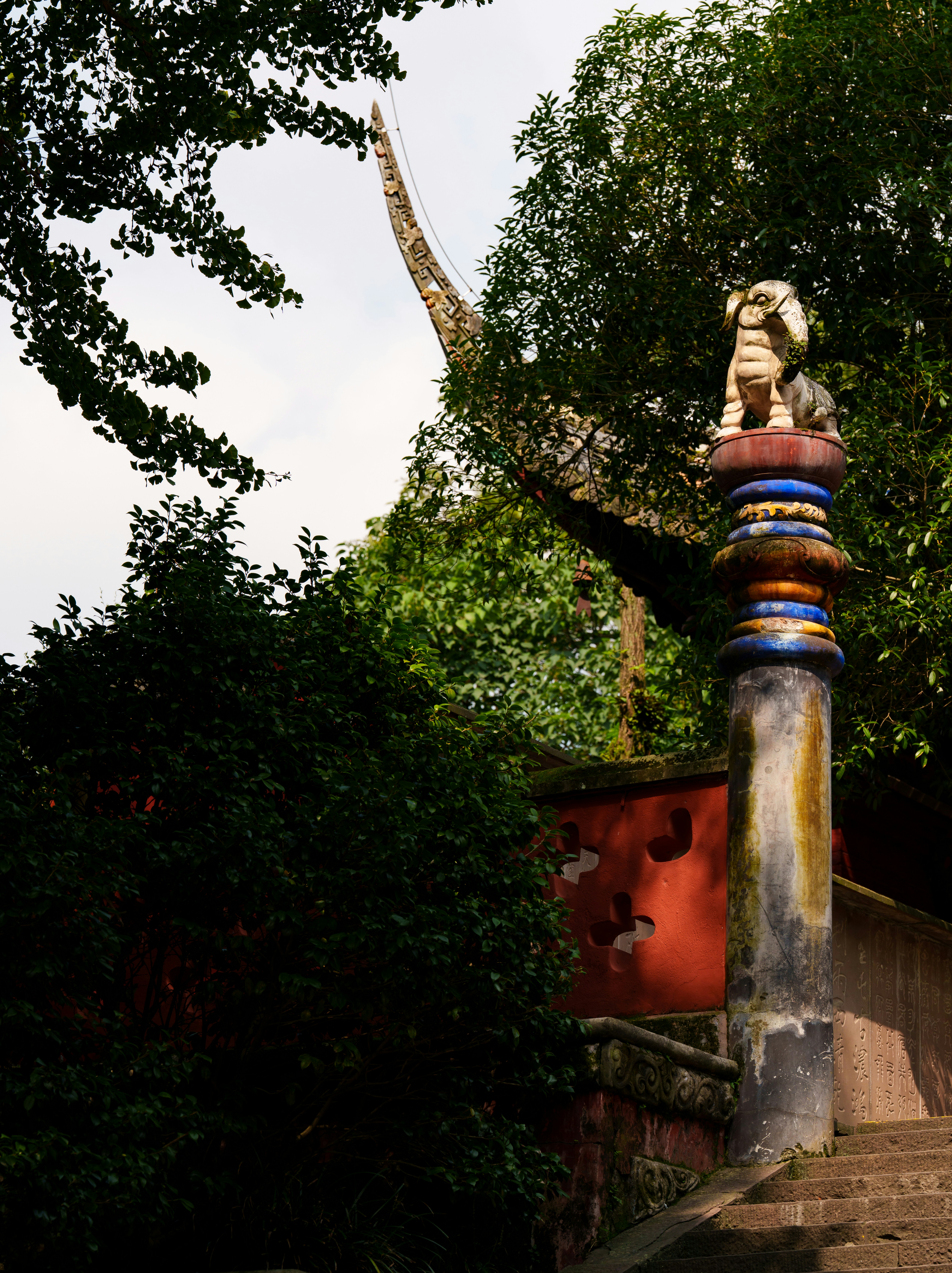 Ornate pillar with a lion statue and trees