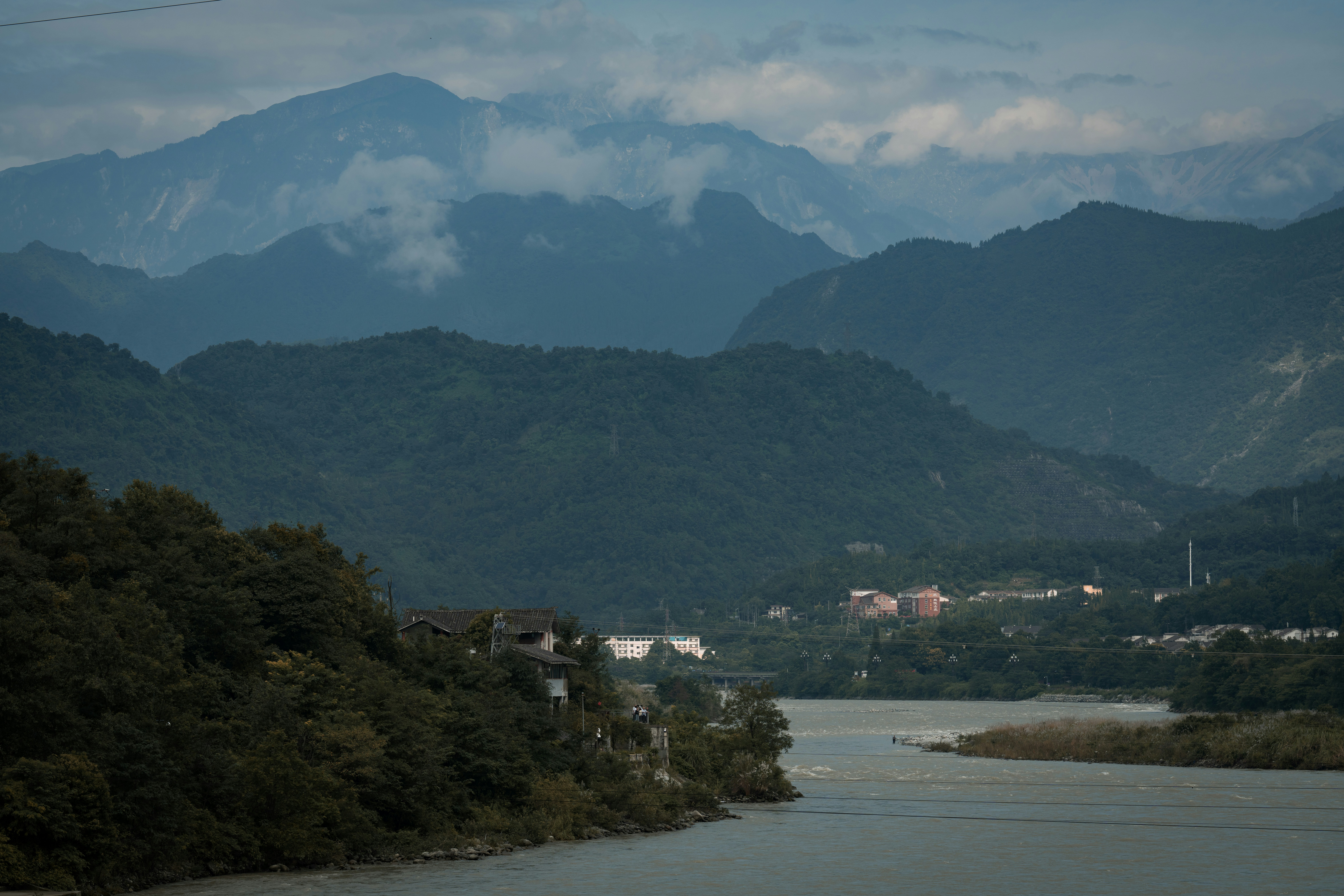River flows past forested hills towards distant mountains.