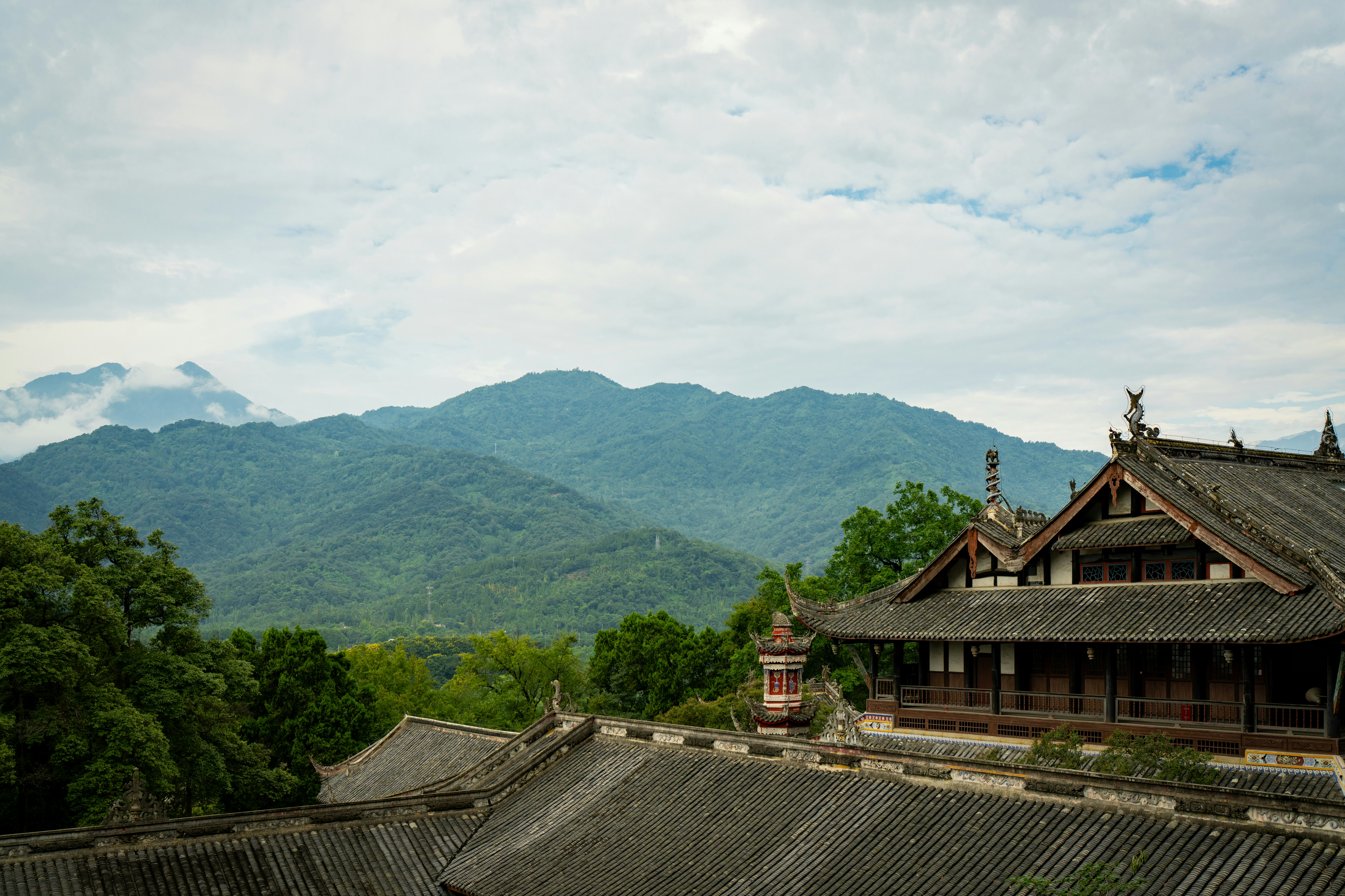 Traditional asian architecture overlooks lush green mountains.