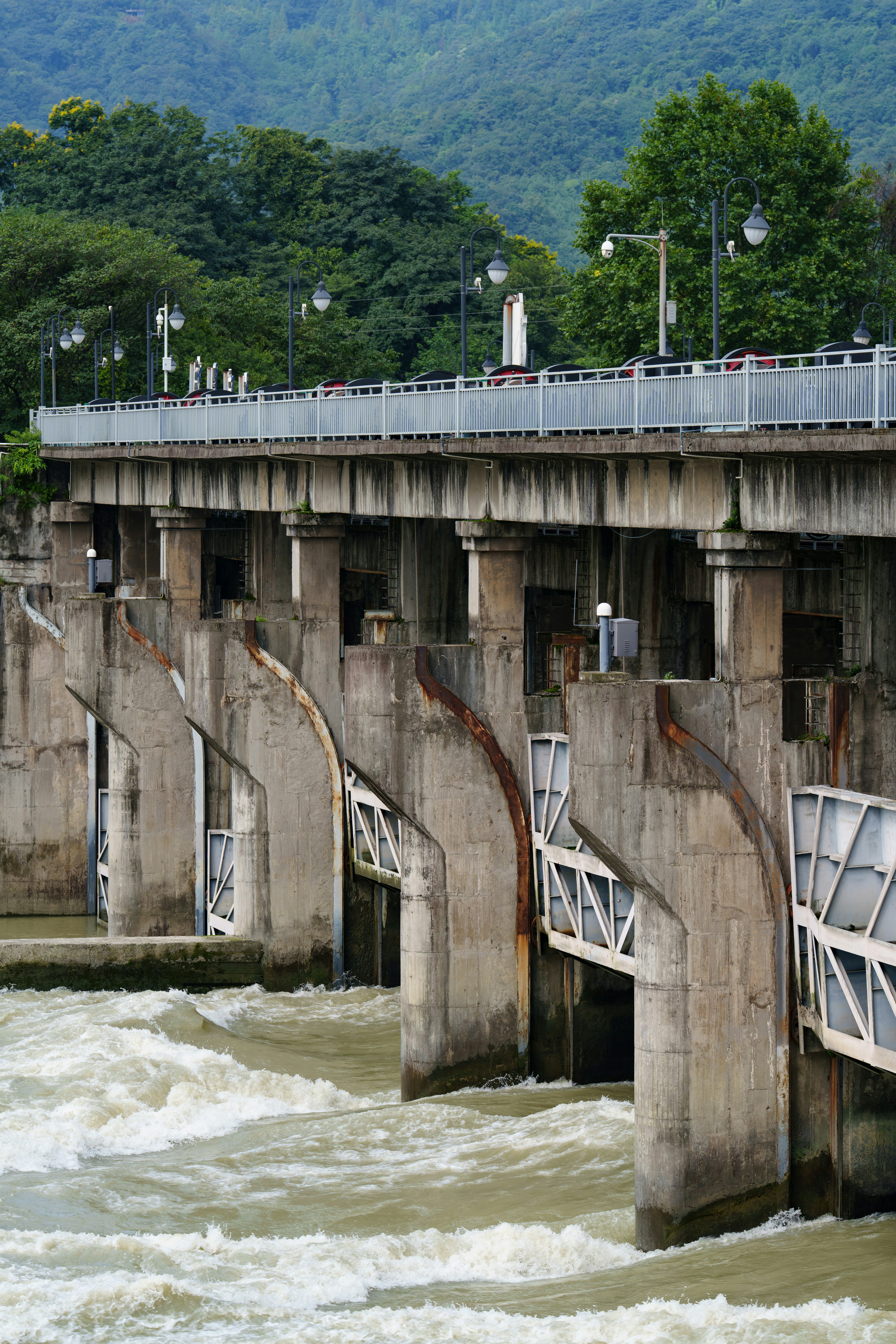 Concrete bridge structure with robust supports overlooking churning river waters, showcasing engineering and nature's power.
