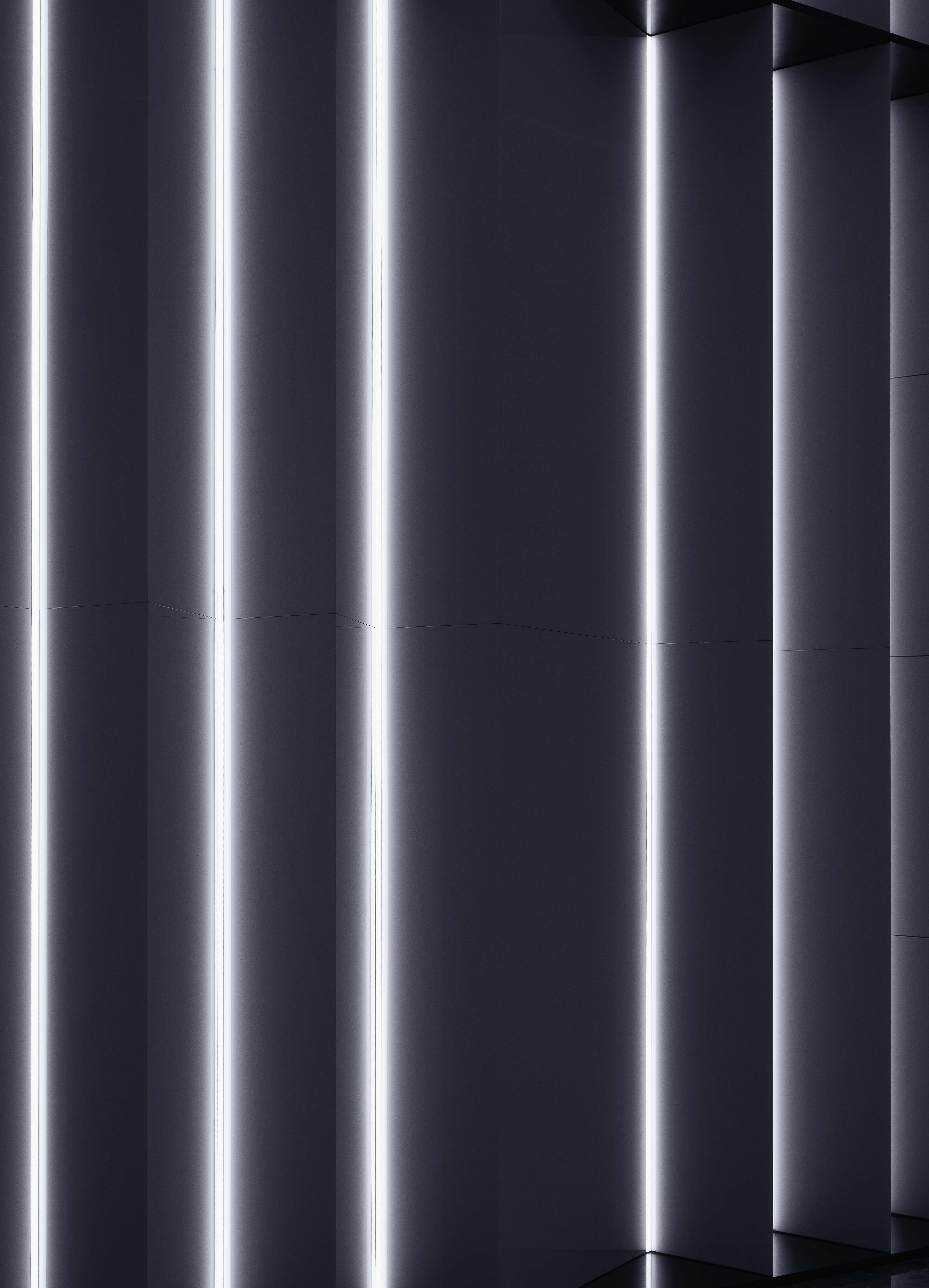 Vertical white lights on a dark textured wall