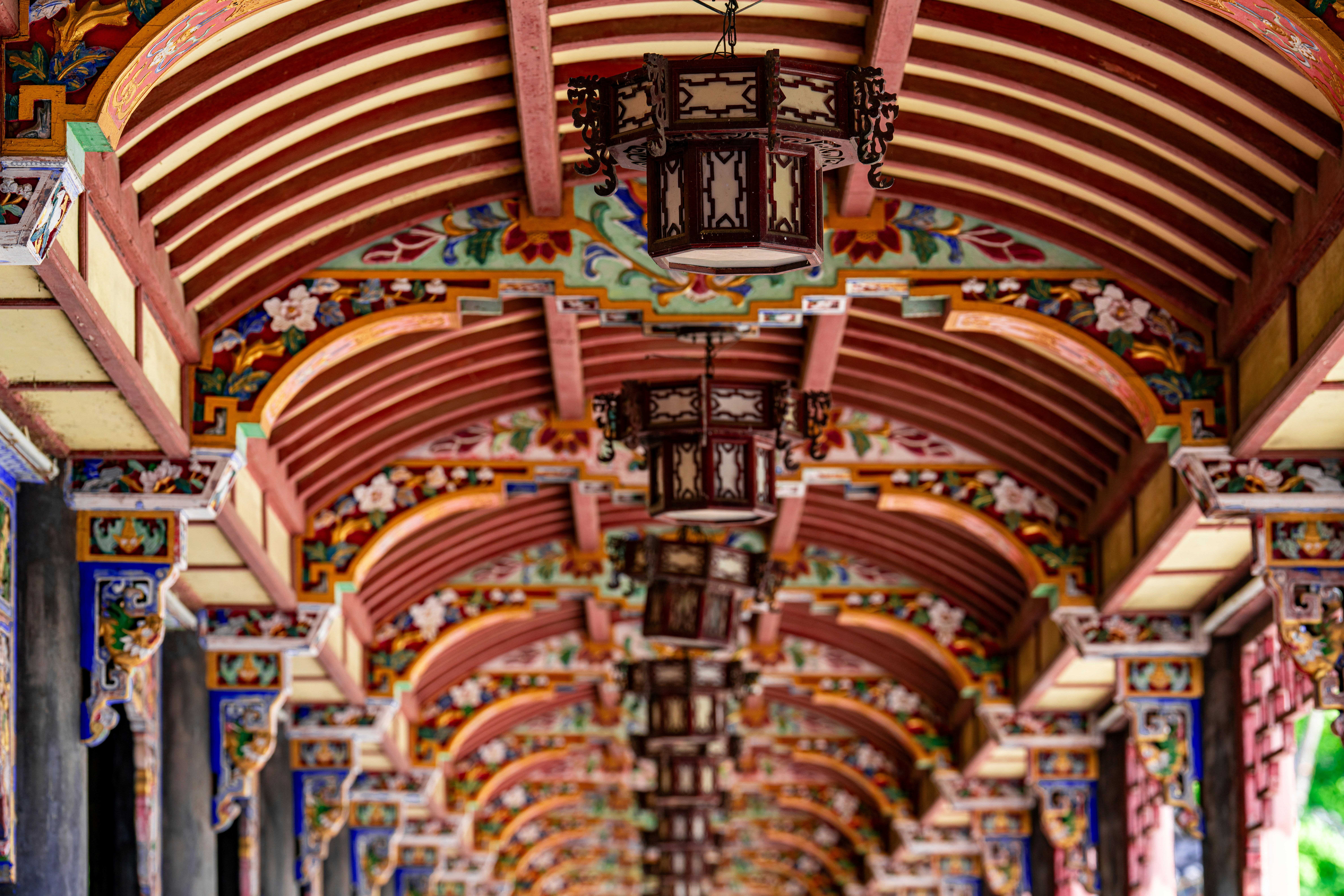 Lantern-lit Corridor: A Tapestry of Painted Beams and Repeating Arches