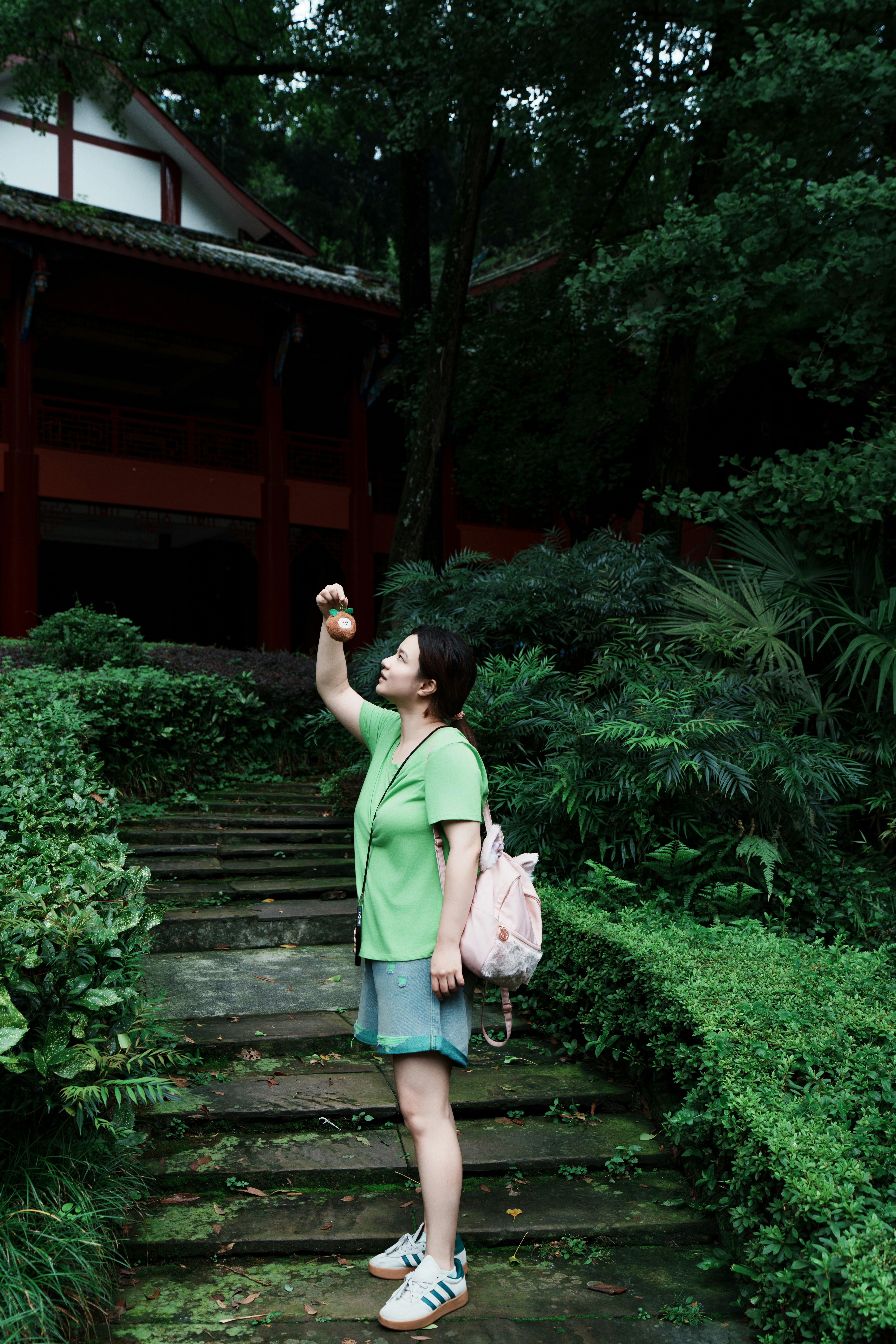 Lime-Green Explorer on Mossy Steps Examines an Apple by a Red-Temple Gateway