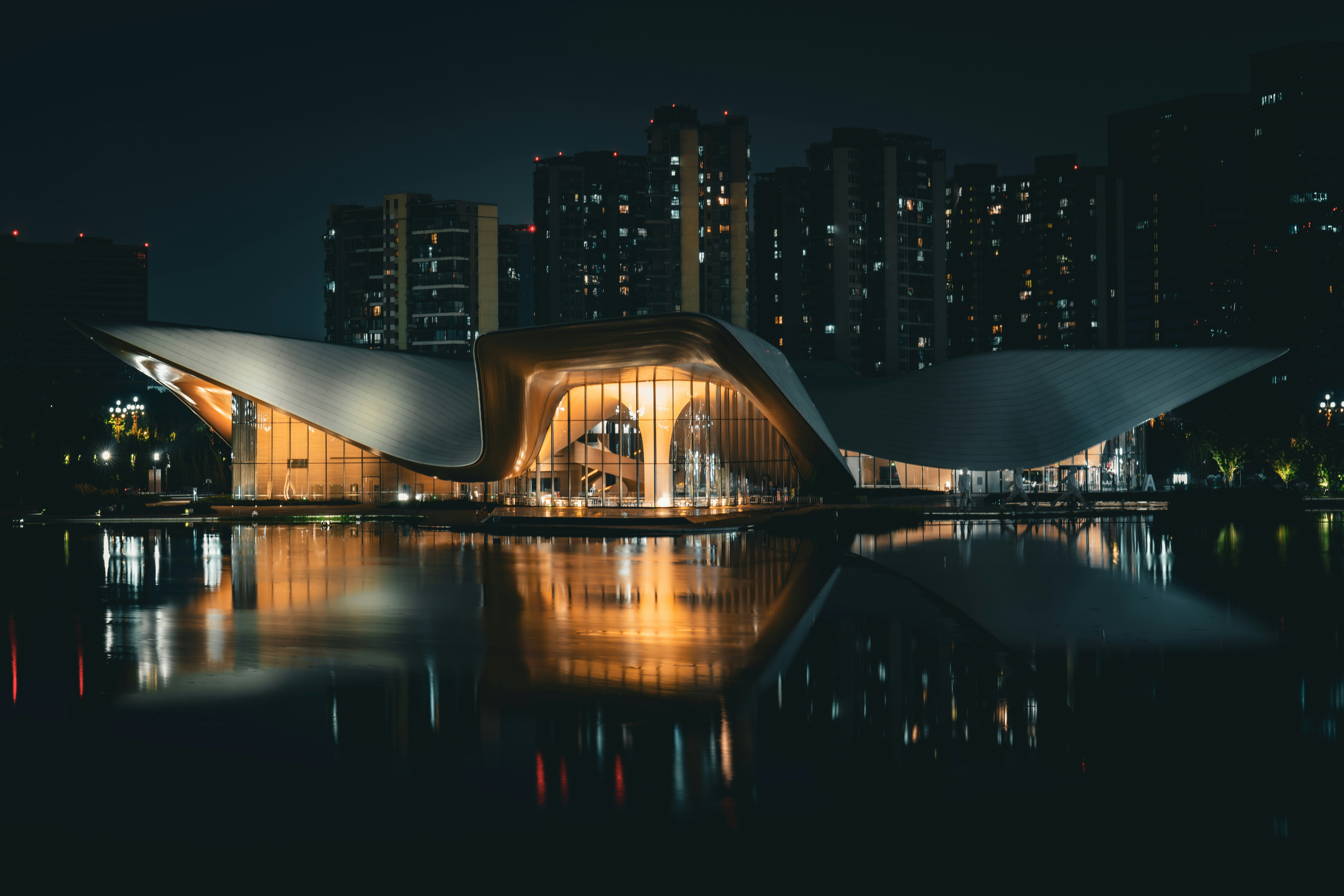 Modern building with glowing windows reflected in water at night