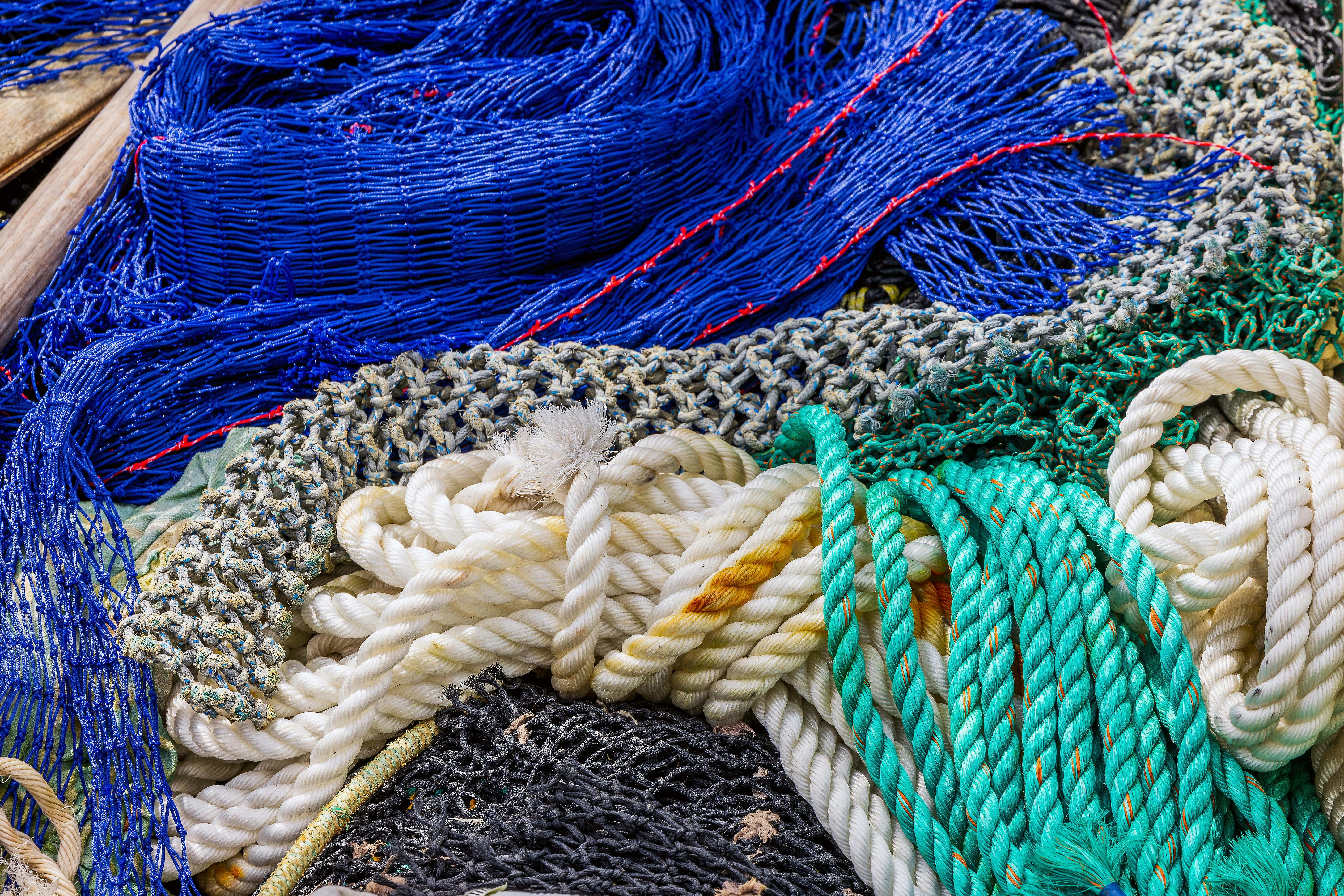 Some contrasting textures and colours of ropes and nets on the deck of a fishing boat. | Pile of colorful fishing nets and ropes
