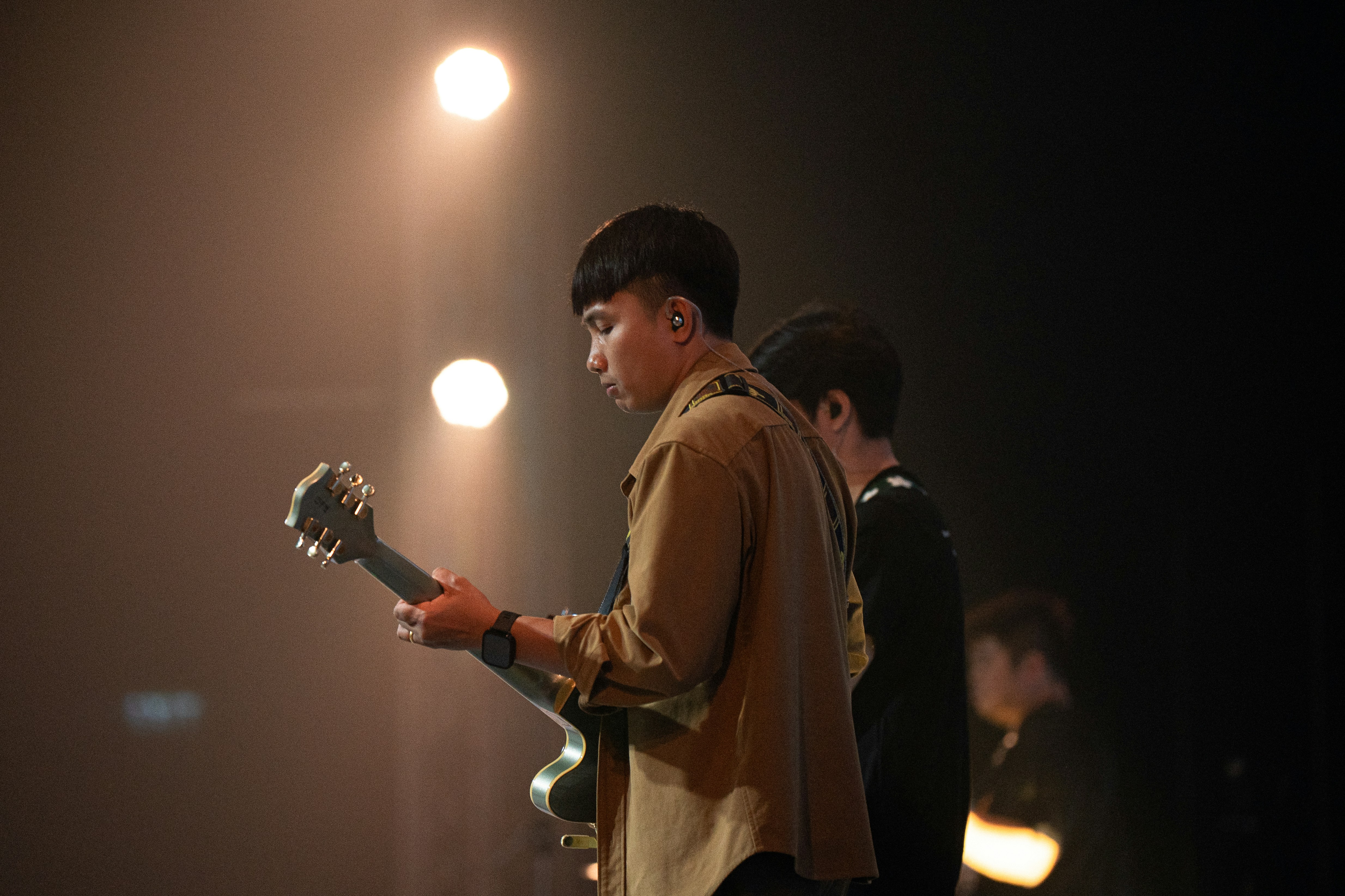 Musicians playing guitars on a dimly lit stage.