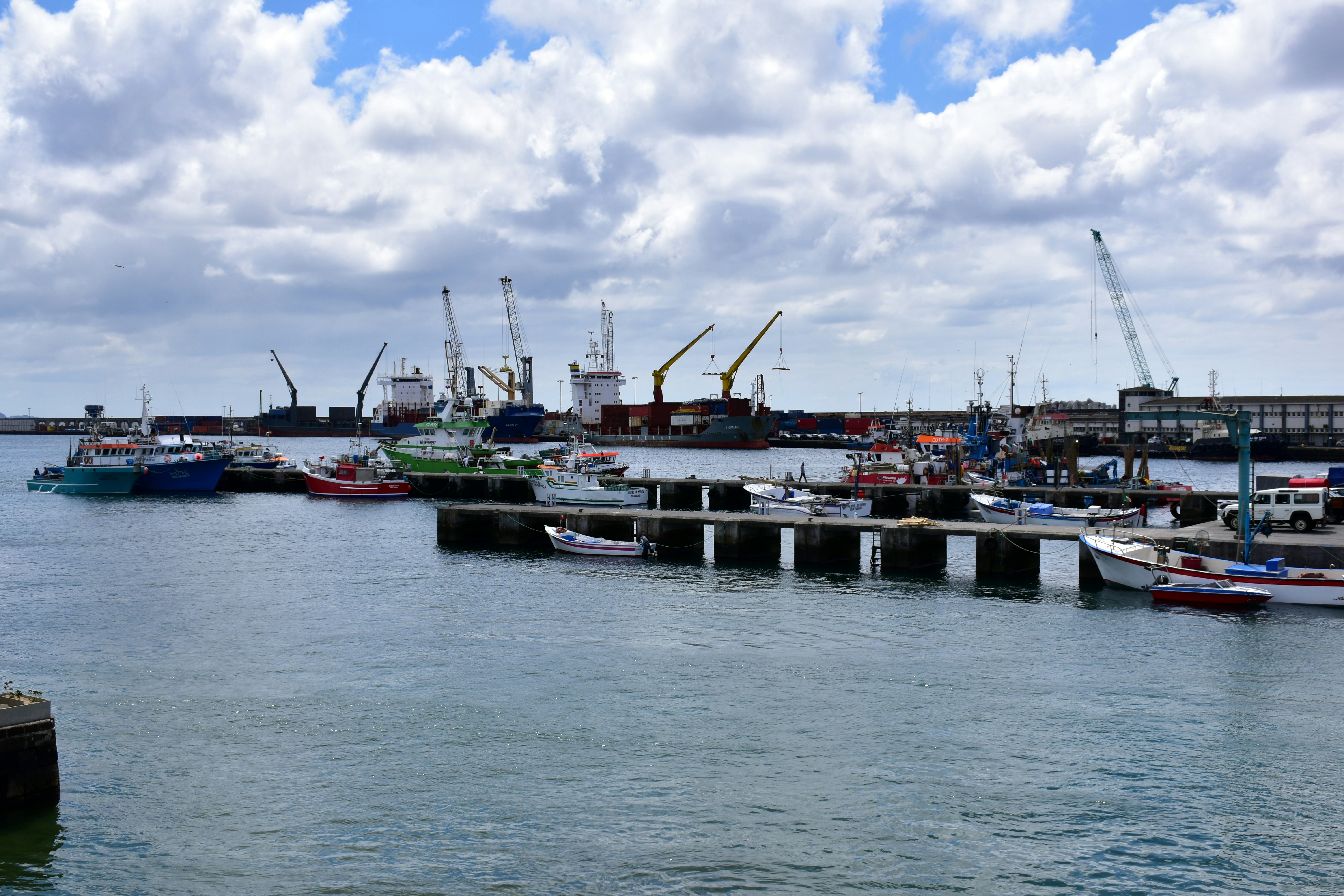 Activity in the port (Azores - travel - cranes) | Boats docked at a busy harbor with cranes in background.