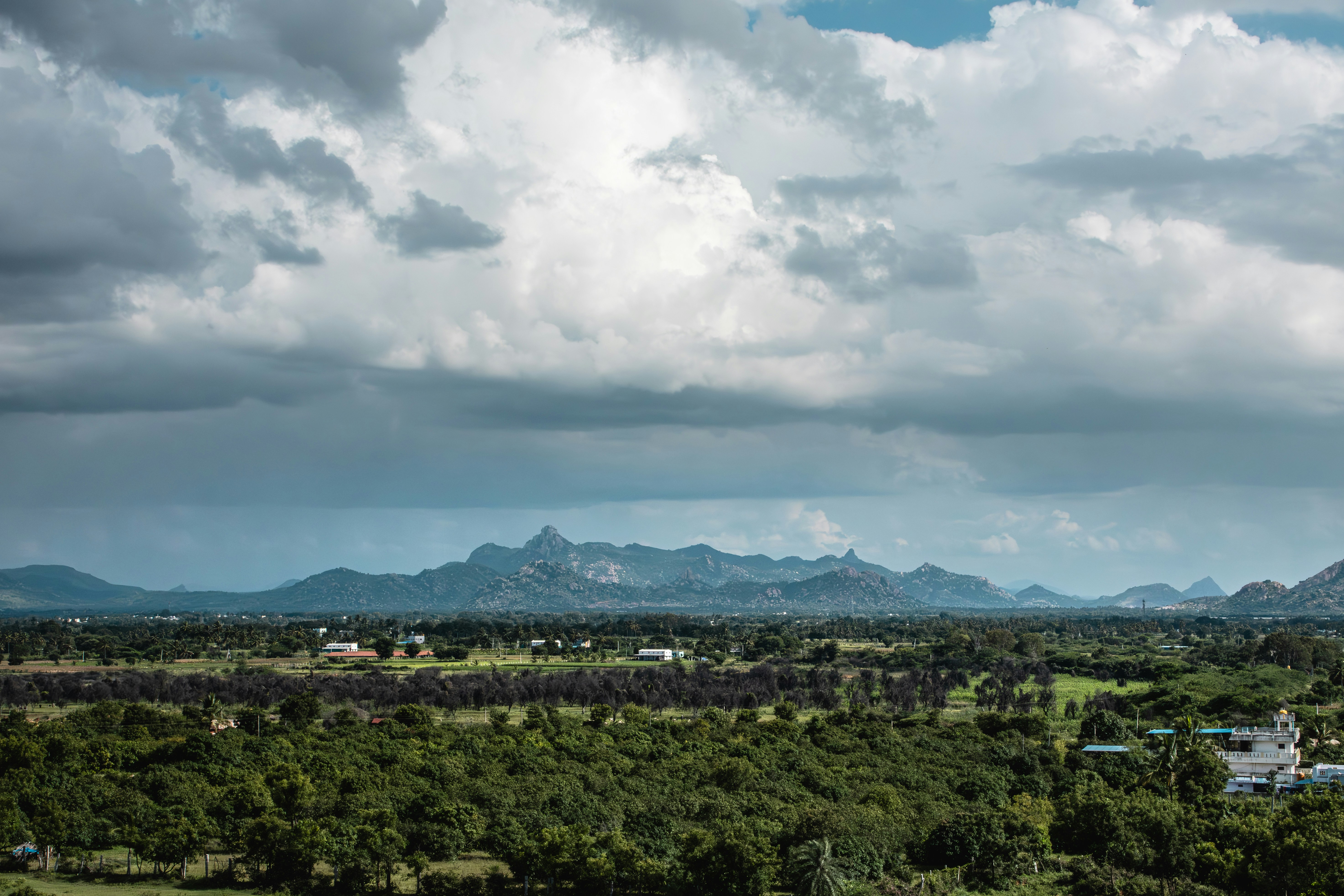 Dramatic clouds over a green landscape with mountains.