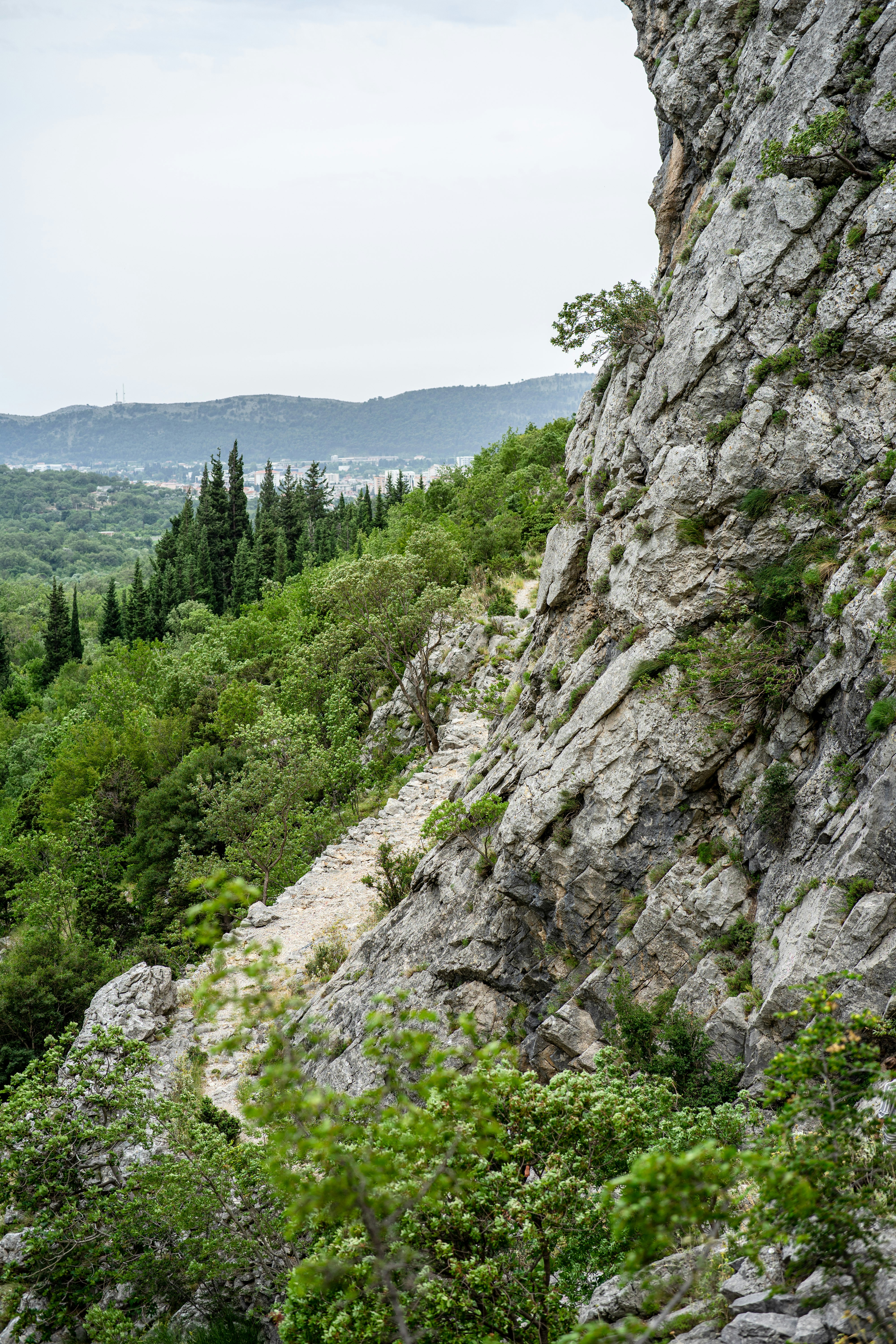Rocky cliffside path leading to a distant town.