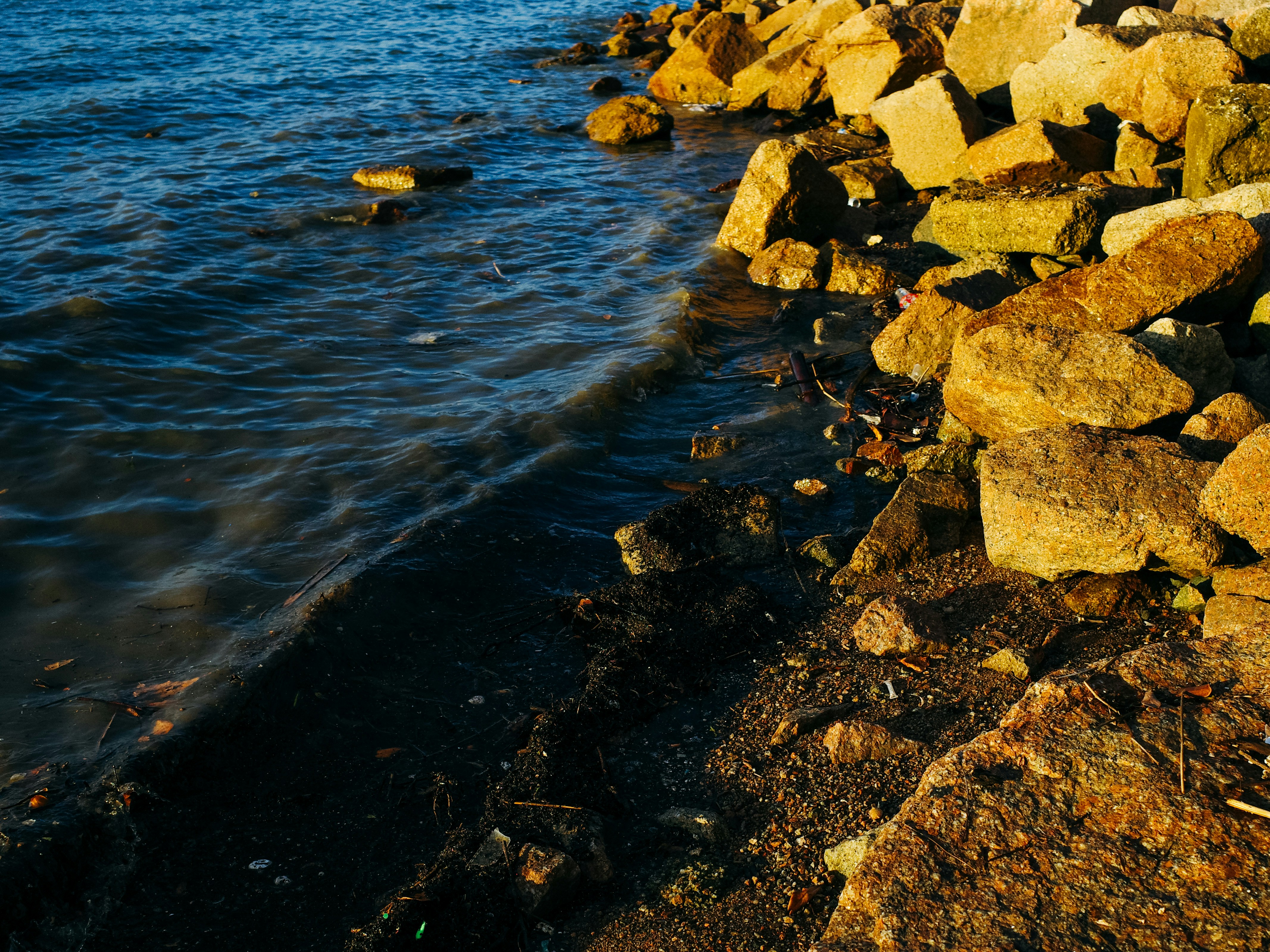Rocky shoreline with dark blue water and stones.