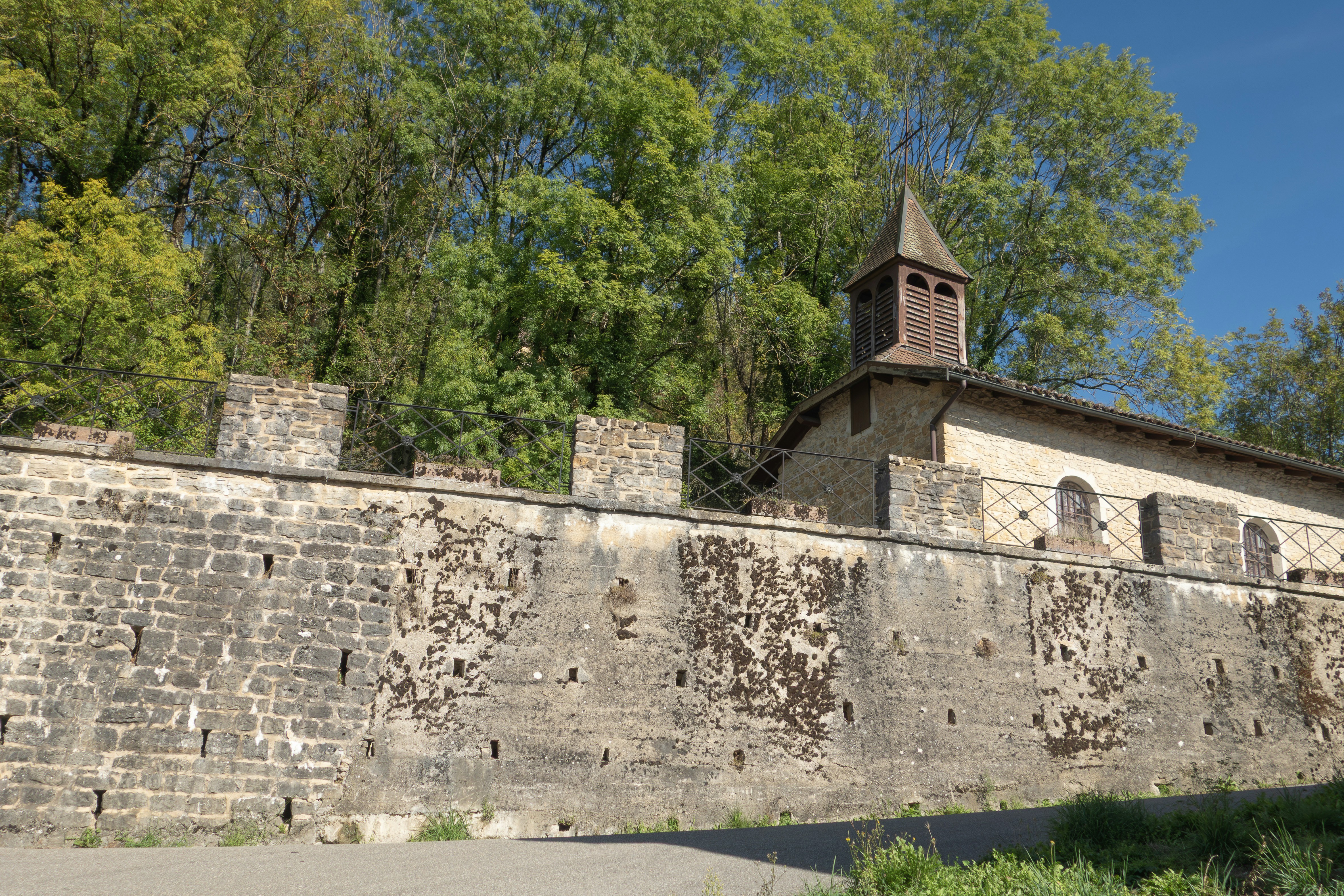 A weathered stone fortress wall with a rustic tower surrounded by lush greenery, showcasing the passage of time.