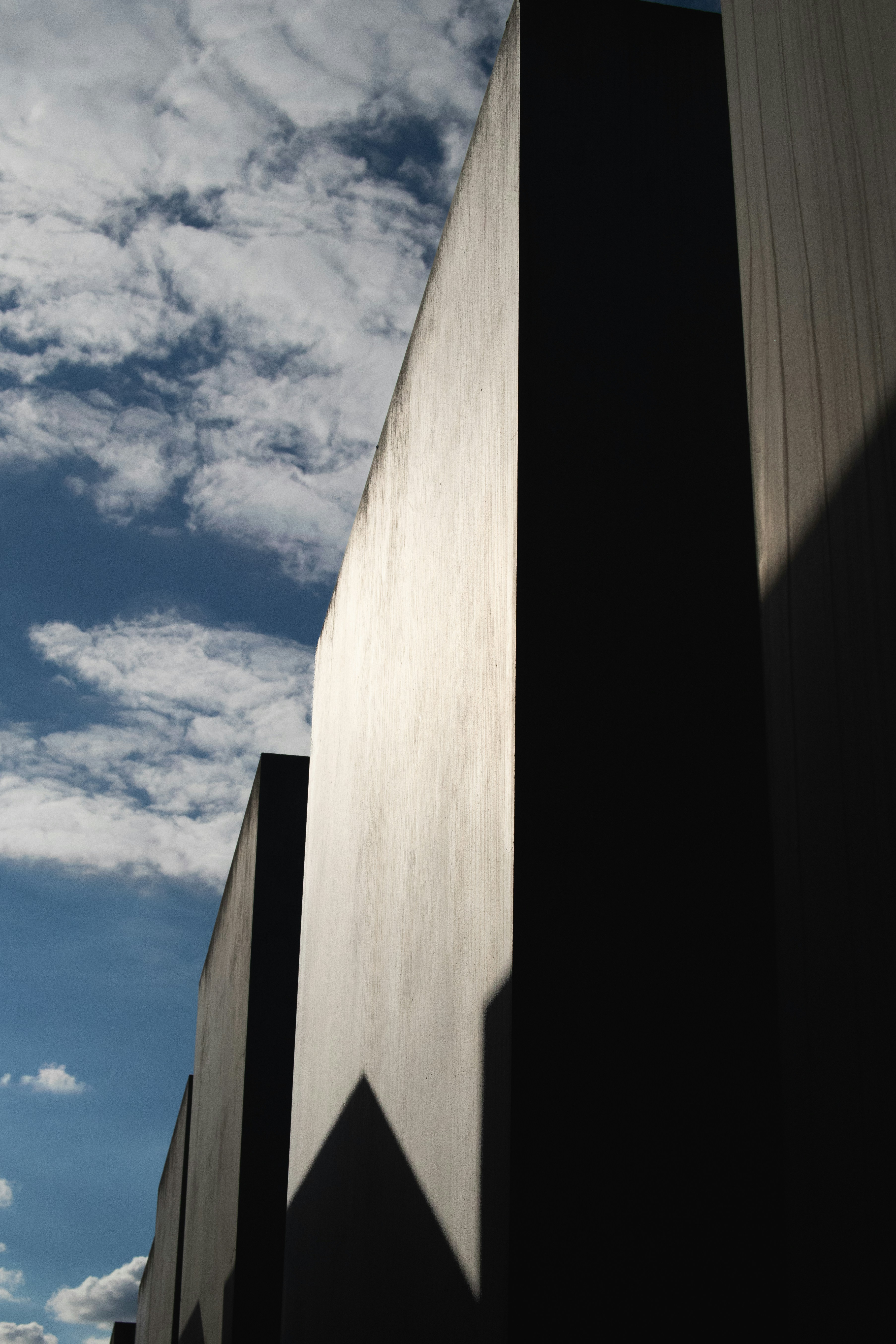 A message shaped icon showing on the side of a pillar in a Jewish memorial center in Berlin | Tall concrete blocks against a cloudy blue sky