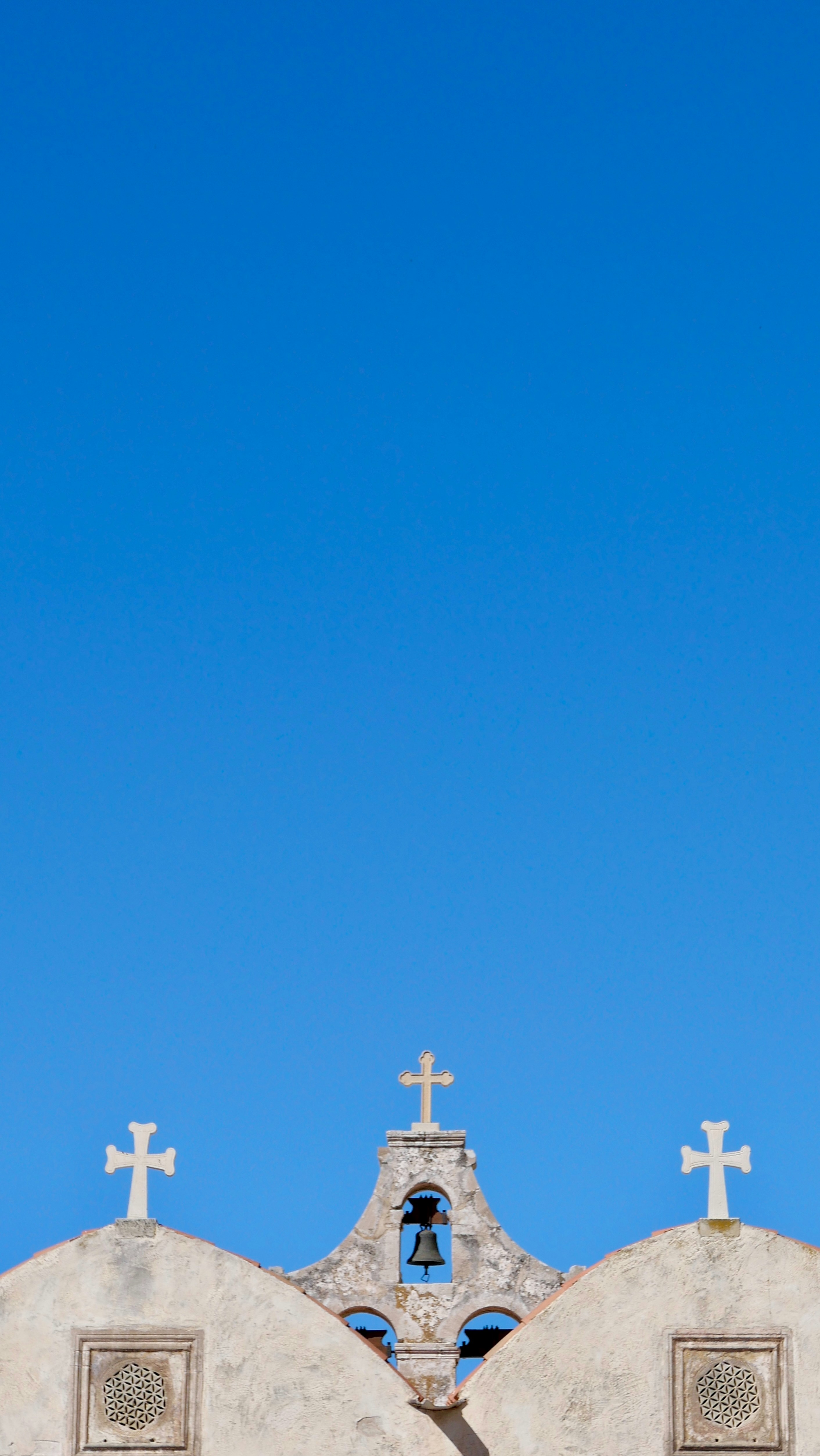 Three crosses atop a building against a blue sky.