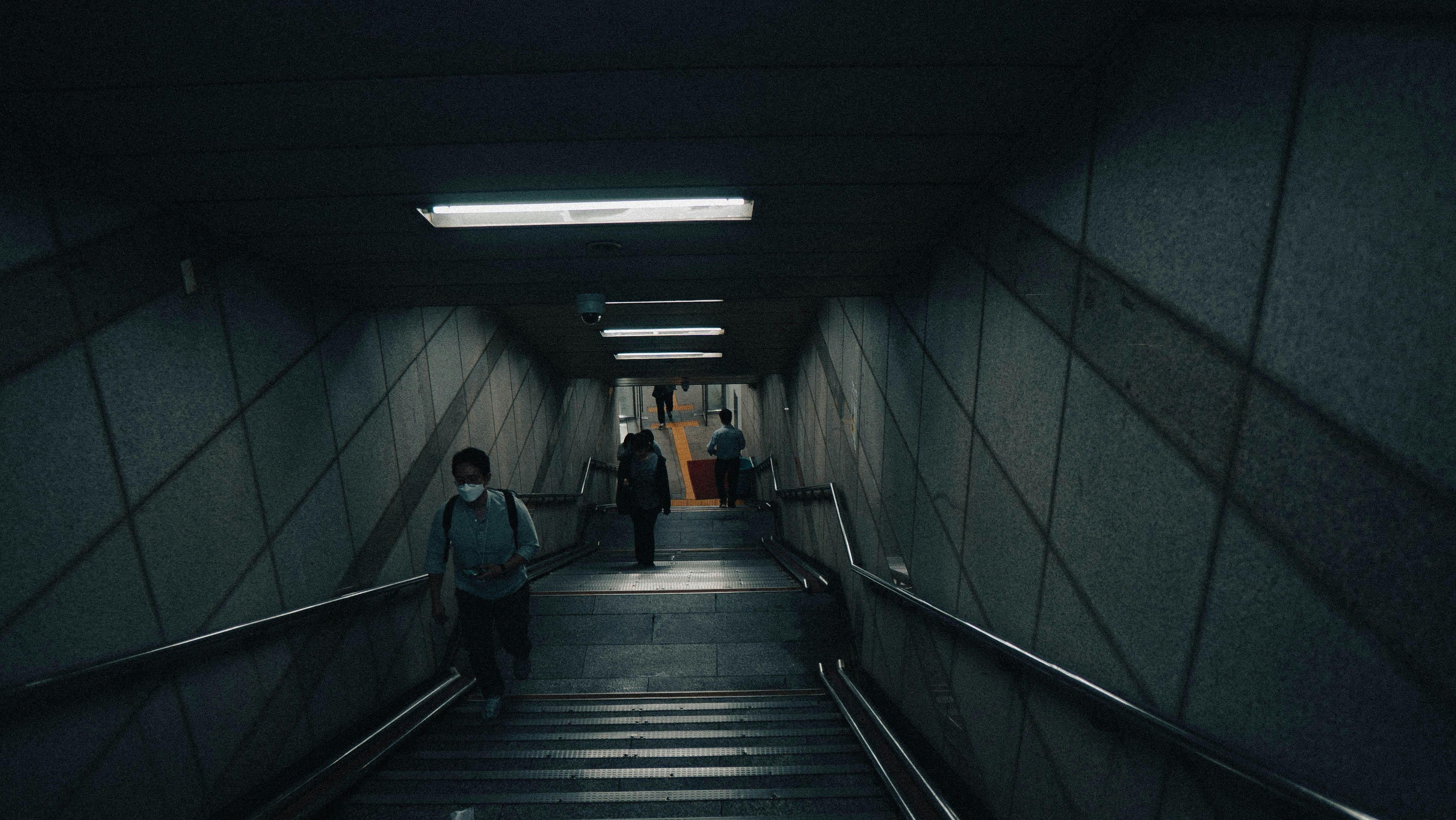 People walking down a dimly lit subway staircase