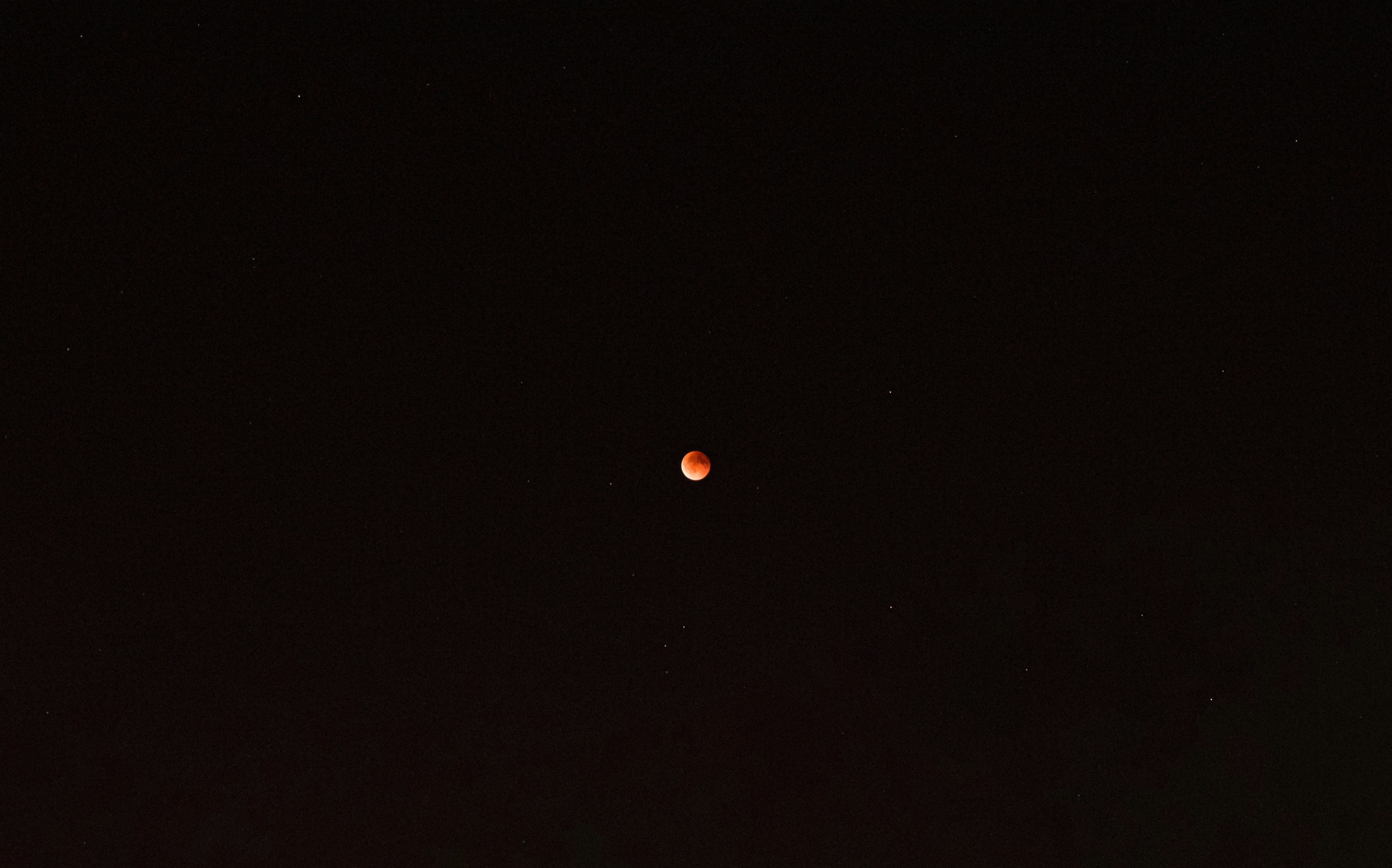 Blood moon glowing against a starry night sky, showcasing the beauty of a lunar eclipse.