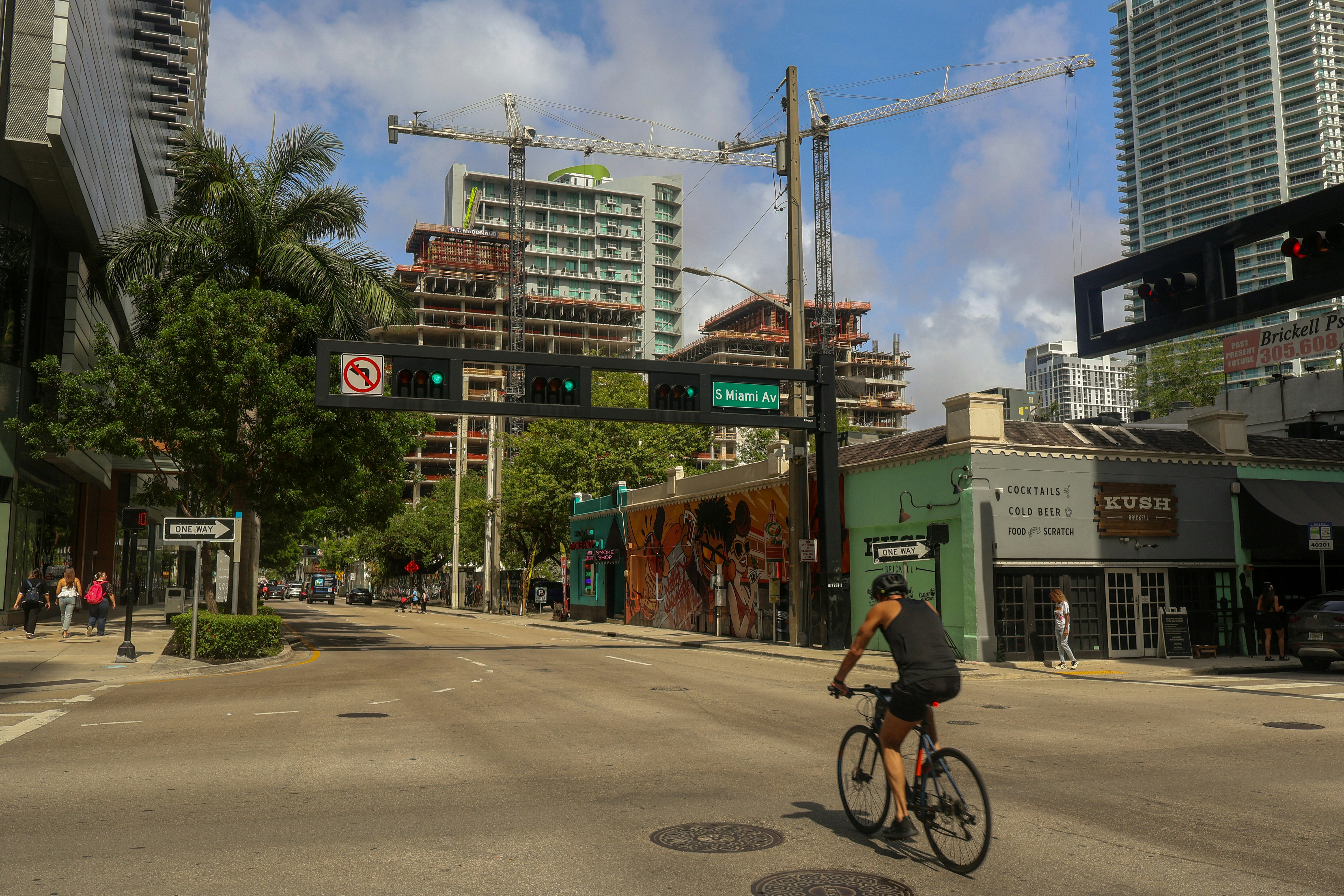 Por Miami te puedes sorprender y cada foto Cuenta. | Cyclist rides down a city street with buildings and buildings.