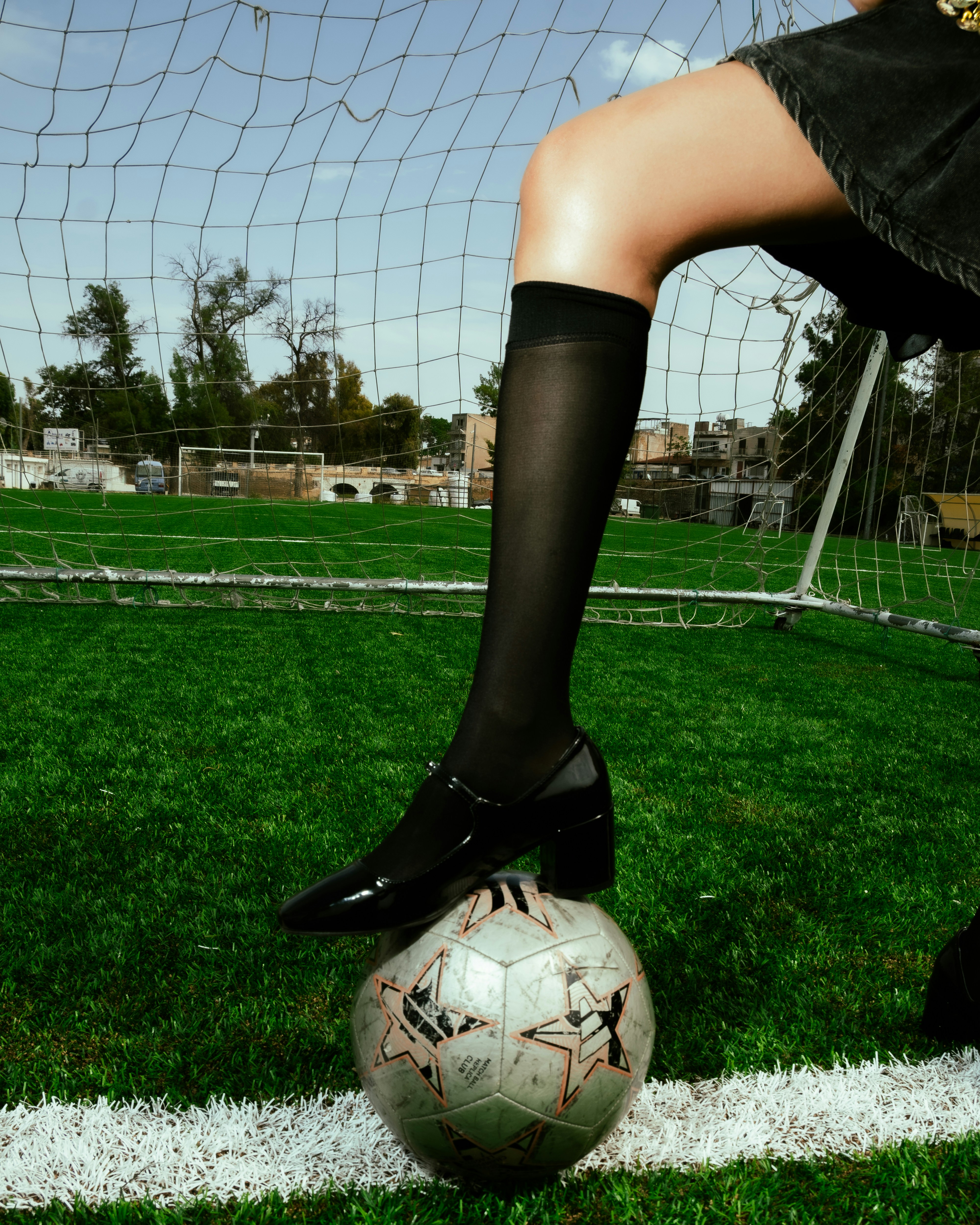 FASHION MEETS SPORT | Woman's leg in black sock and shoe on soccer ball