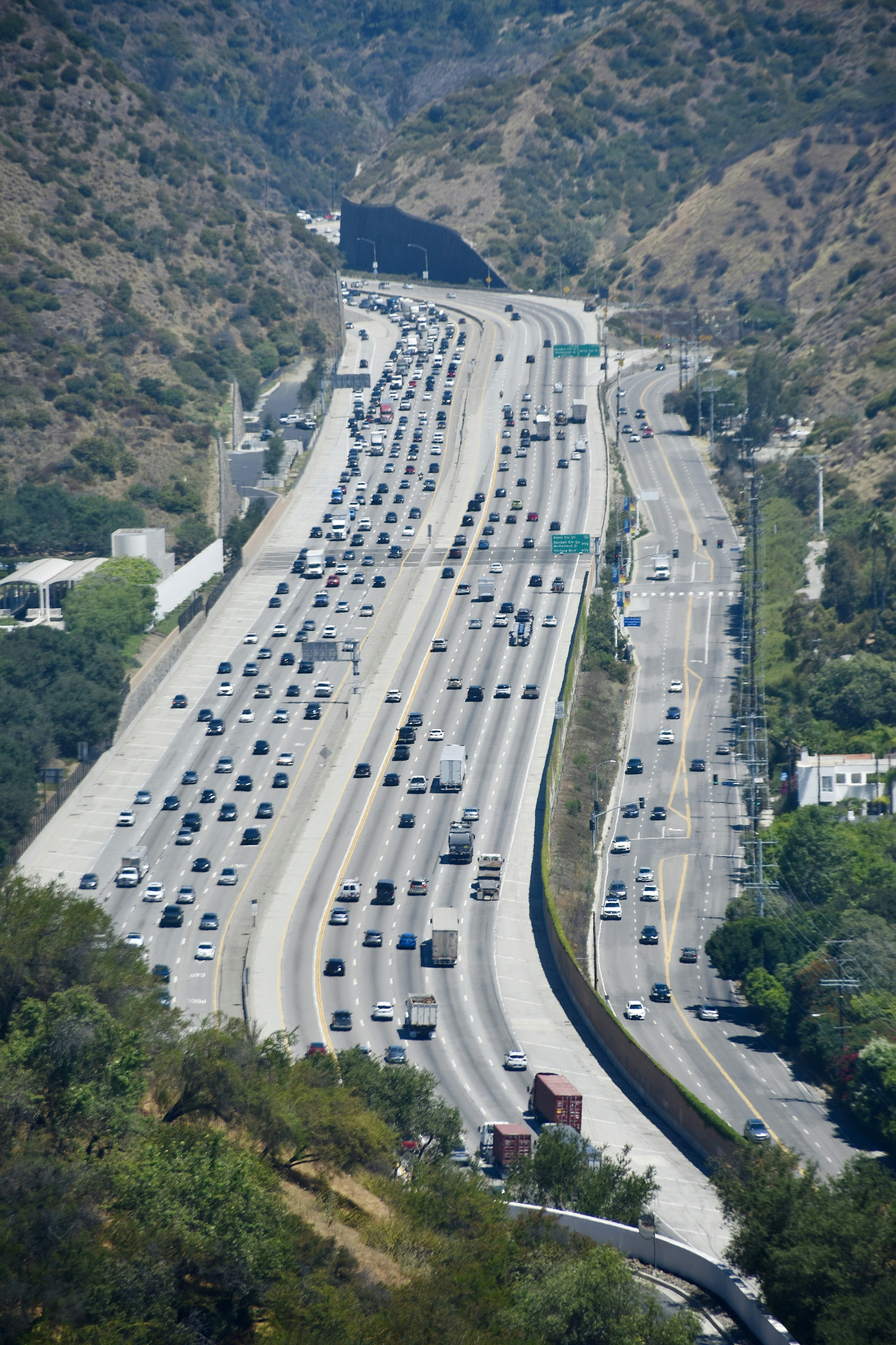 I think that is the 101 highway leaving L.A. to the northwest | Heavy traffic on a multi-lane highway through hills.