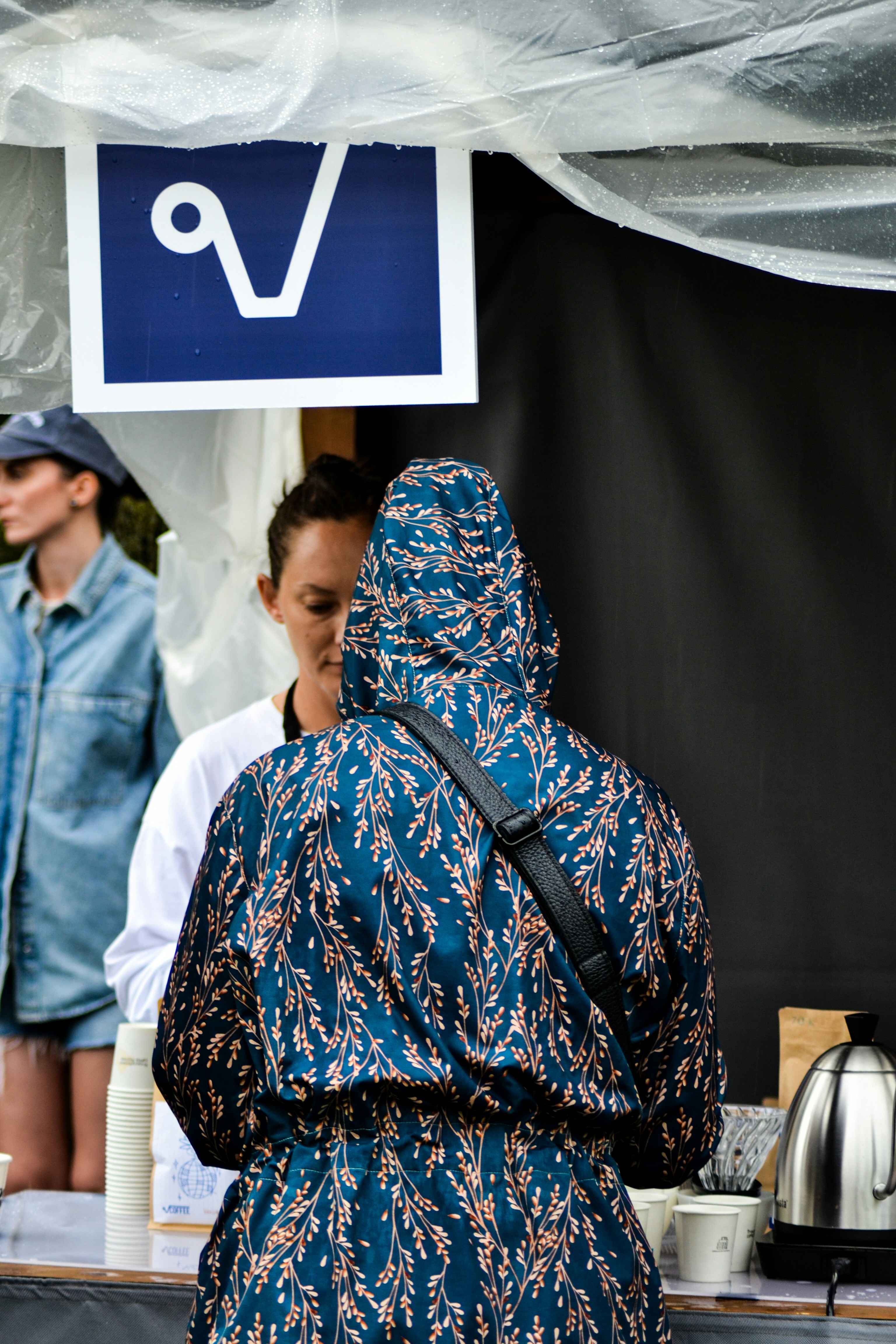 Floral-Patterned Hoodie Anchors Attention at a Casual Service Booth