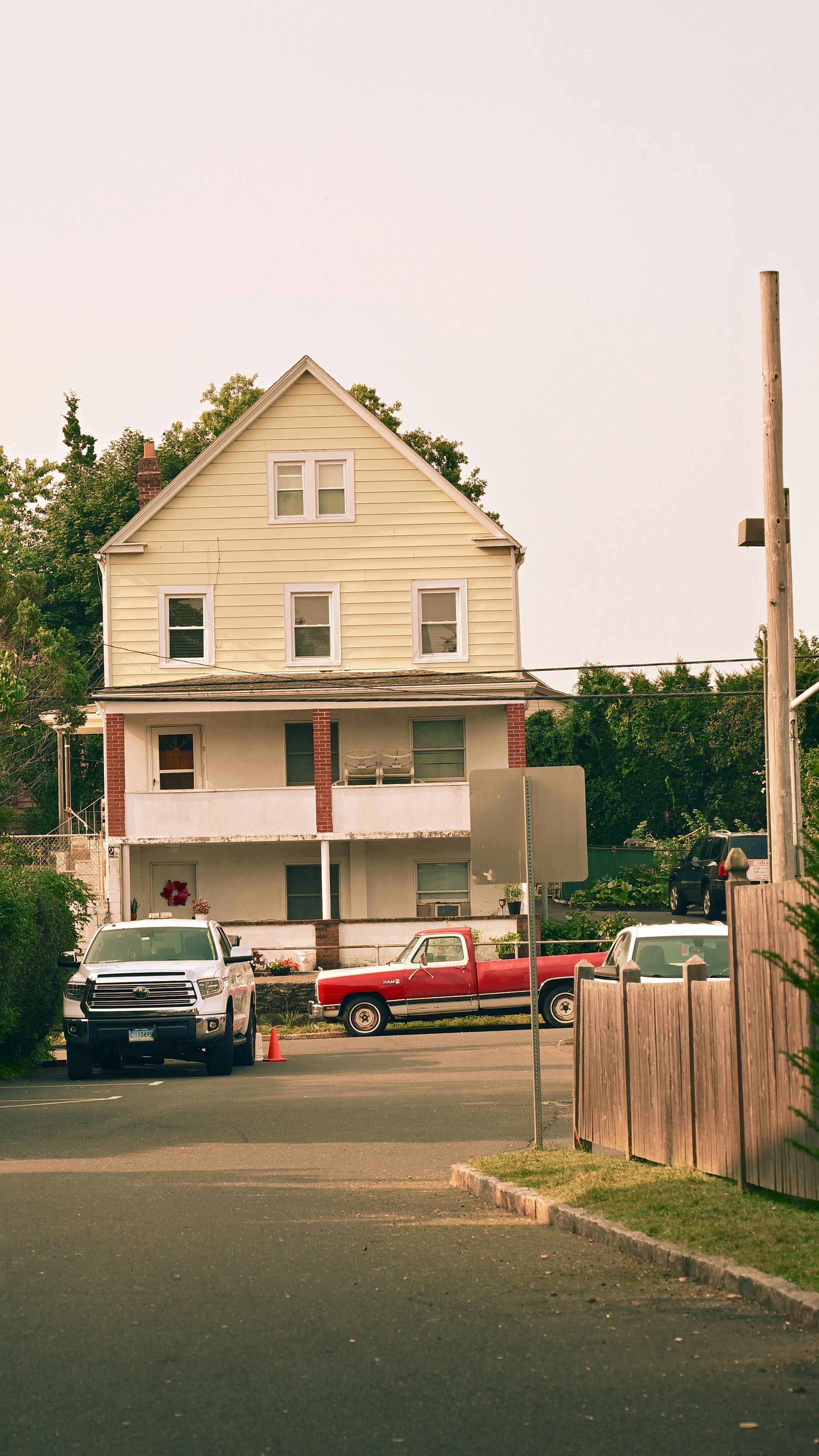 Two-story house with vehicles parked outside.