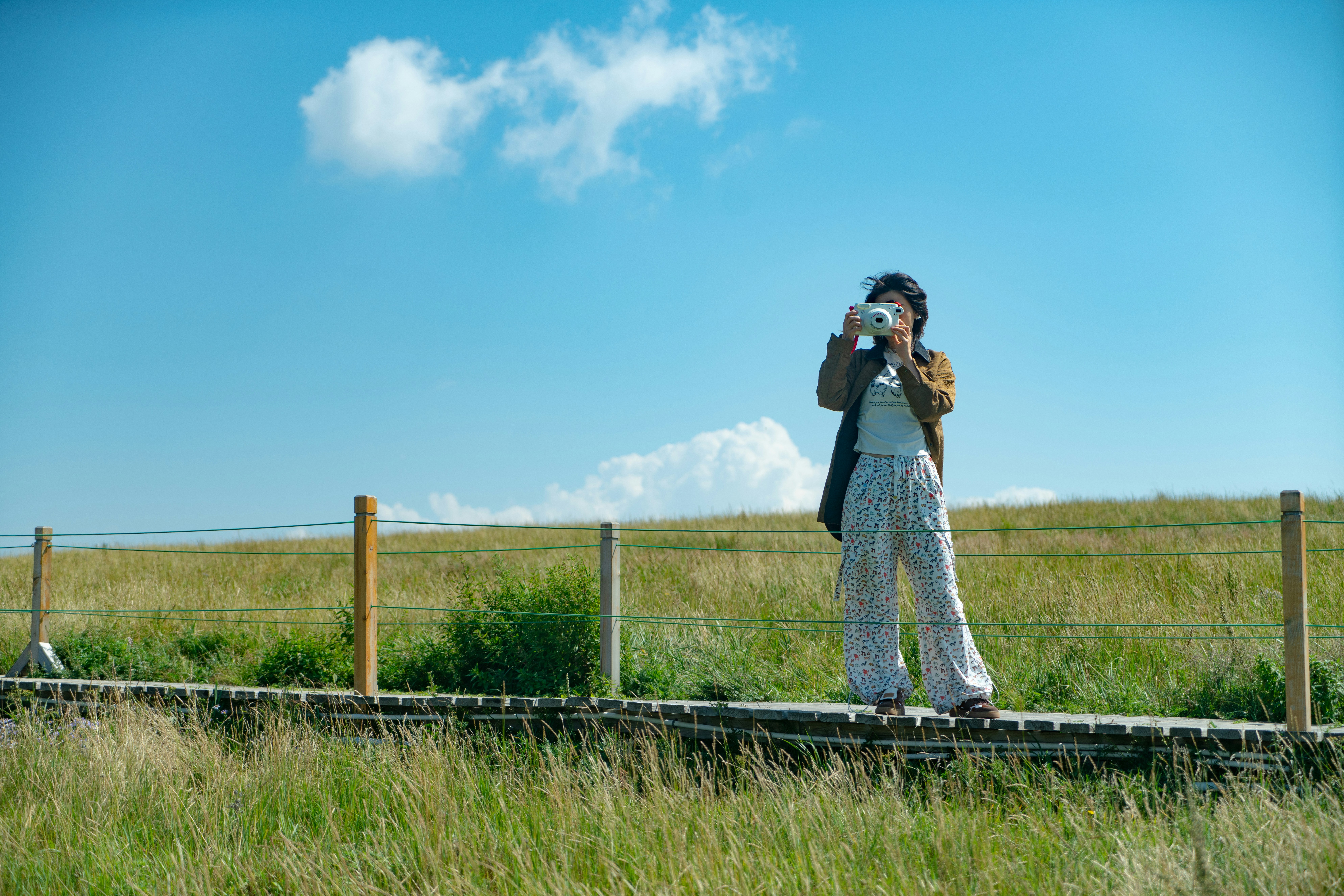 Another Chinese Valentine. We went to Ulanqab and Hohhot to escape from megacity depression. | Woman with camera on wooden path in grassy field.