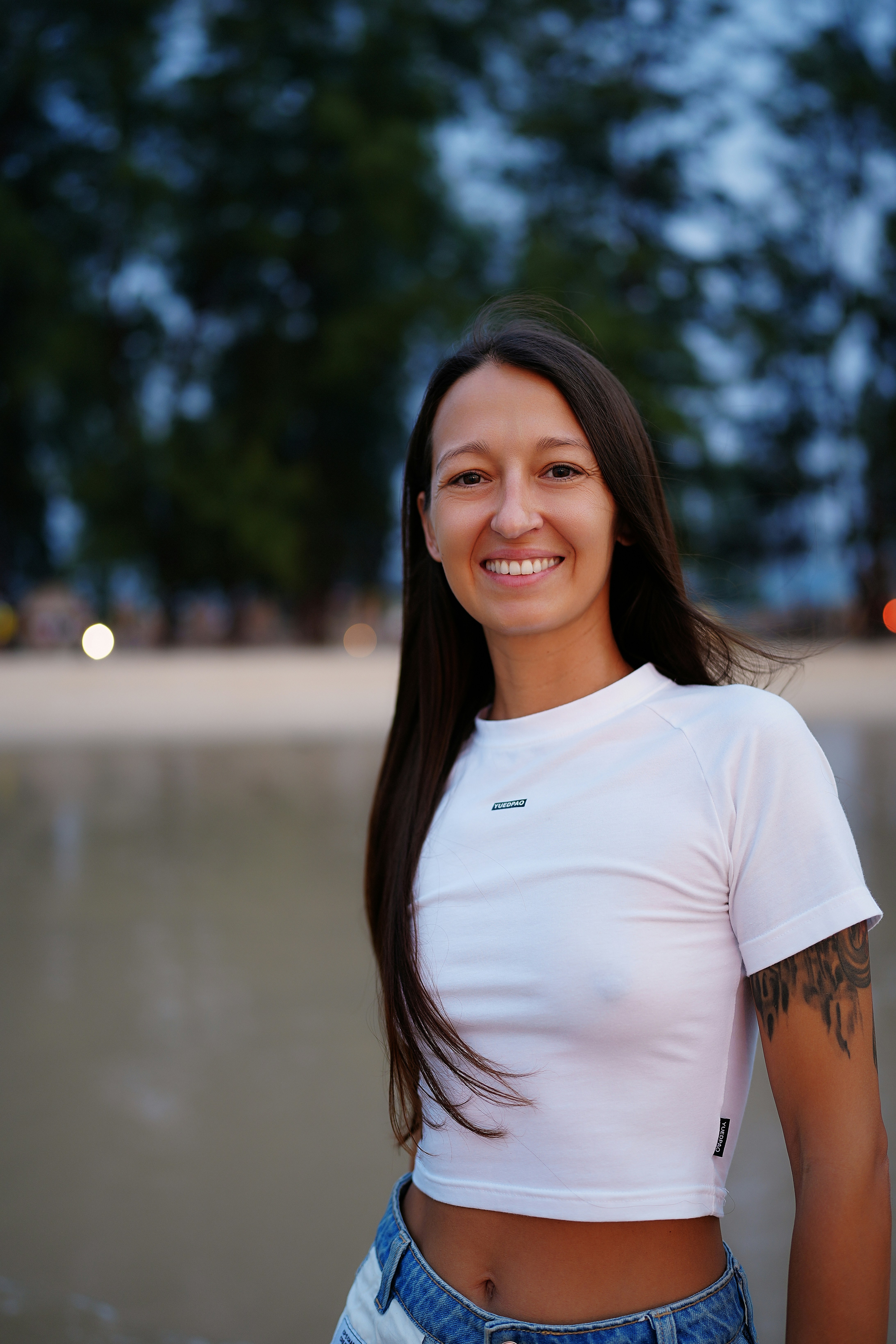 Wind in the hair and a bold look into the lens. Shot on a beach in Phuket, this portrait captures raw energy and emotion, with grainy film-style edit. | Woman smiling on a beach at dusk