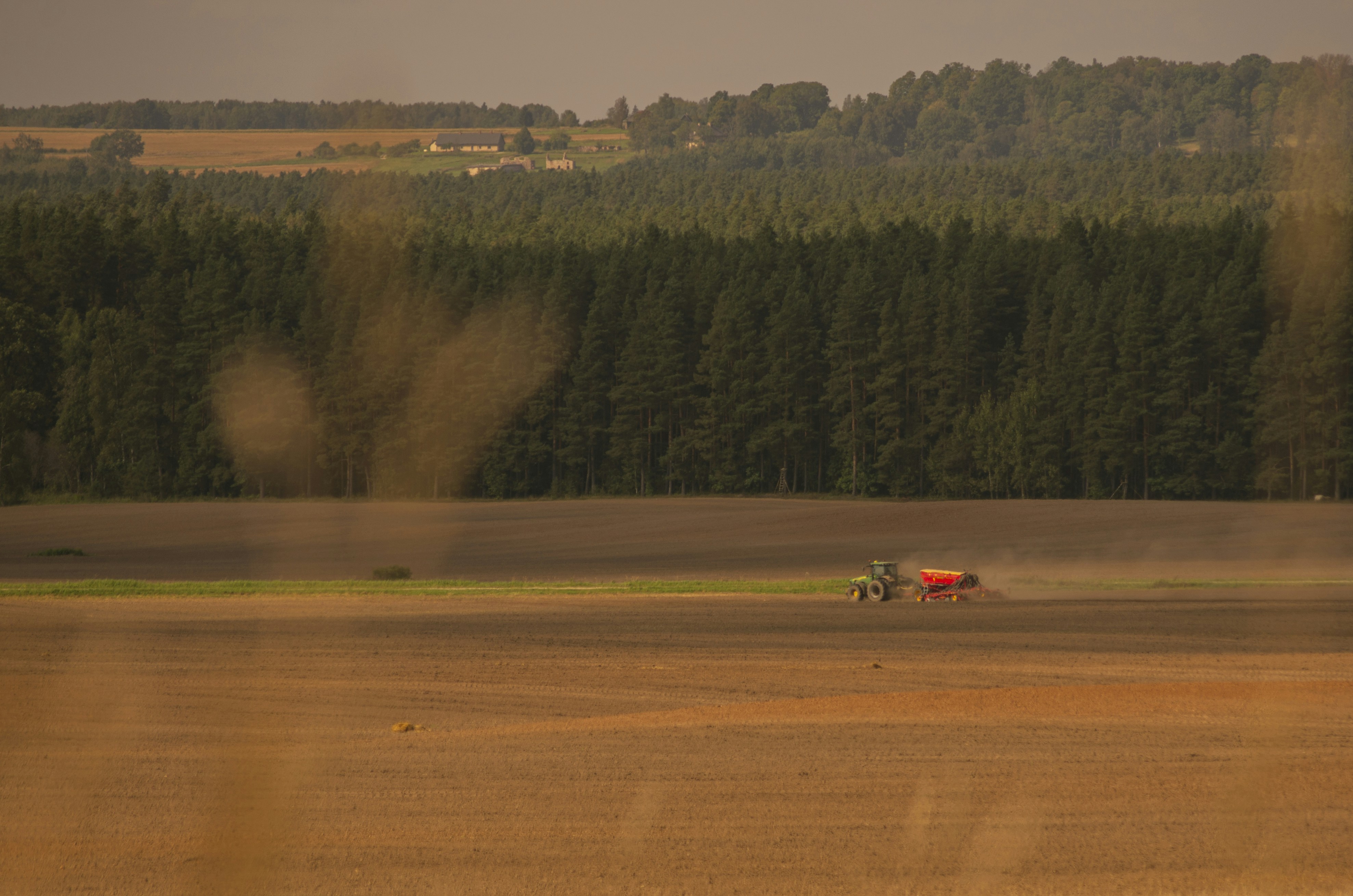 Tractor plowing a field with a forest background