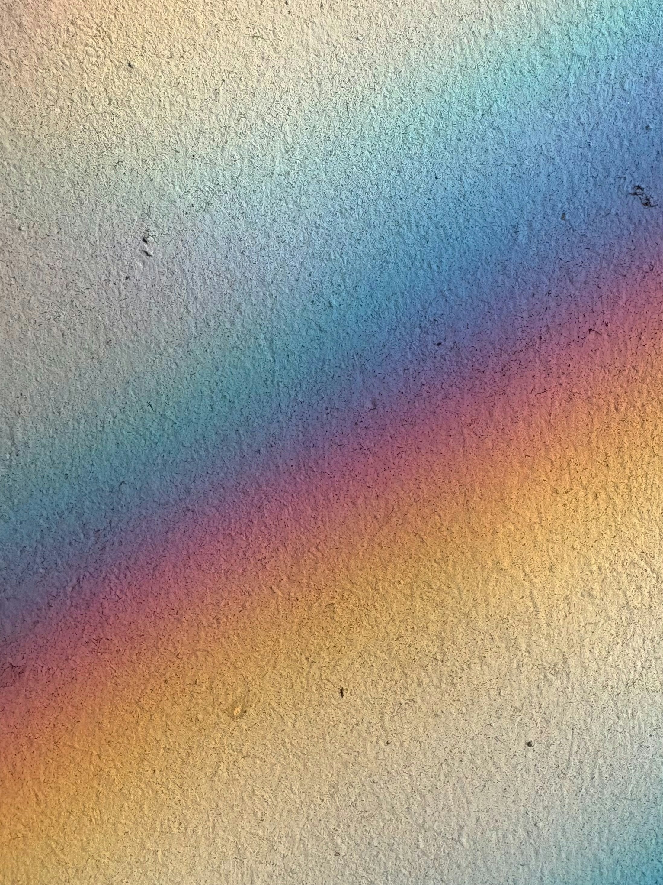 A textured wall with a rainbow light reflection.