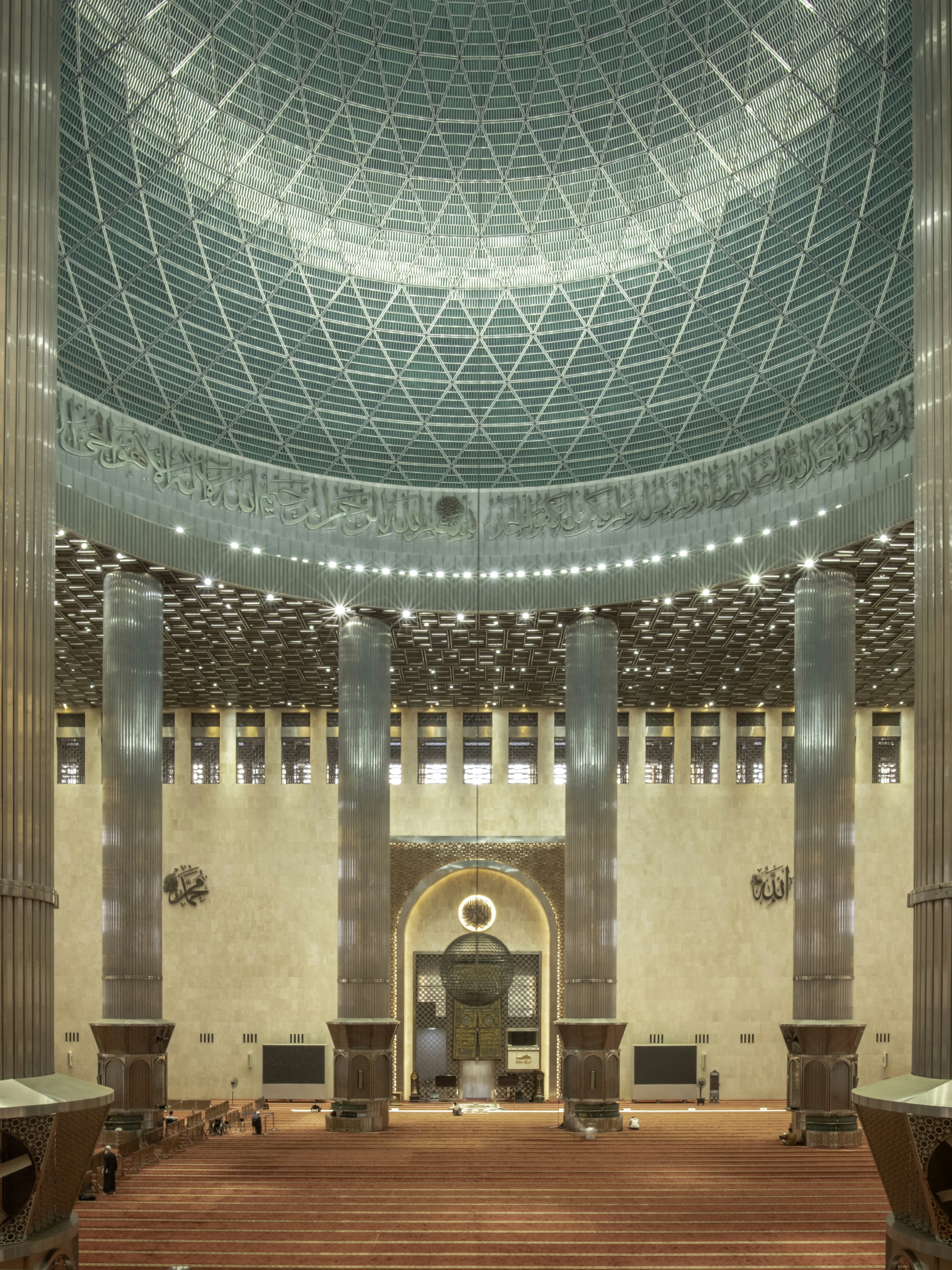 Grand interior of a mosque with tall columns and dome.