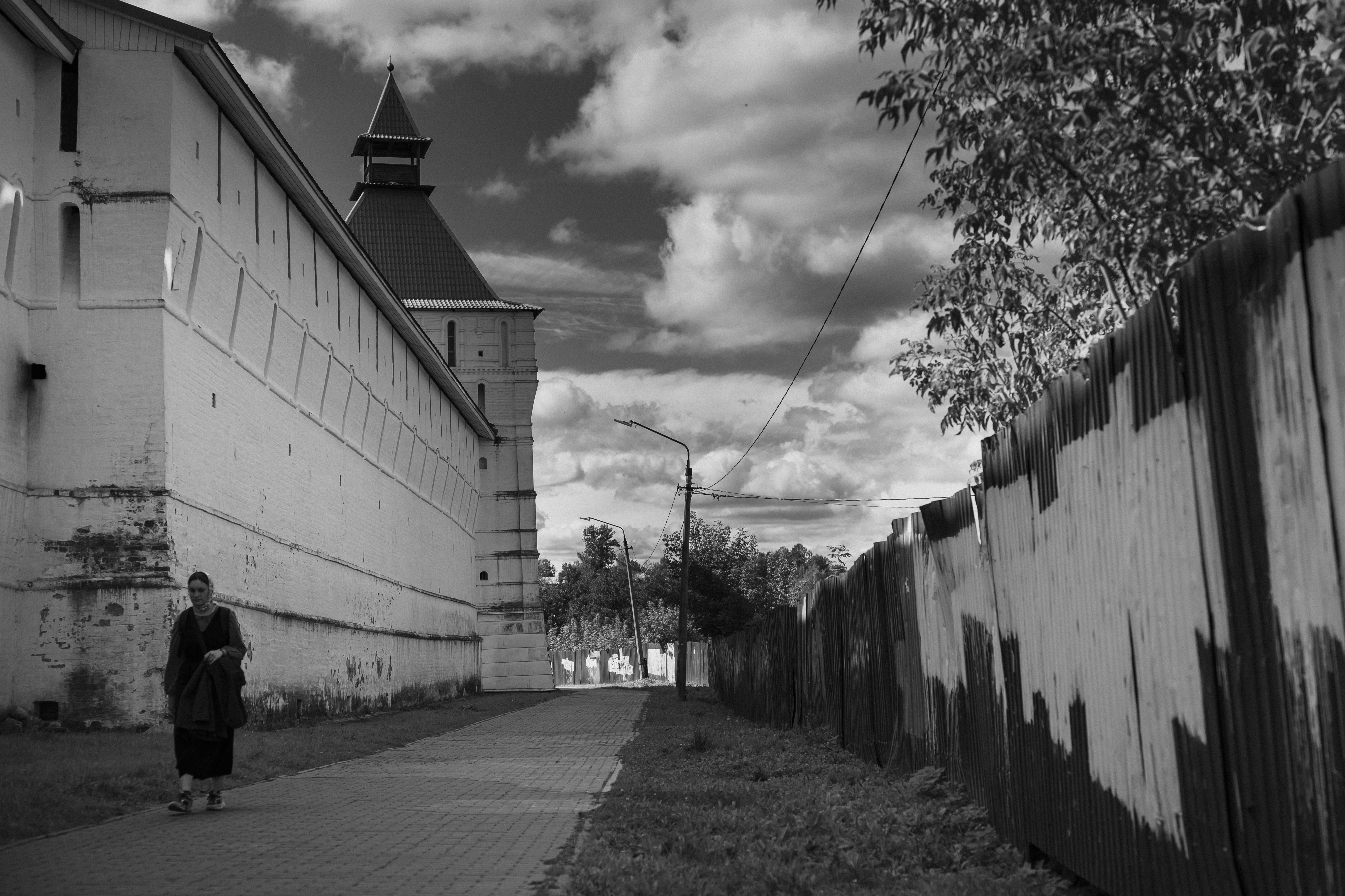 Medieval fortress walls of an ancient Orthodox monastery | A person walks along a path beside a white wall.