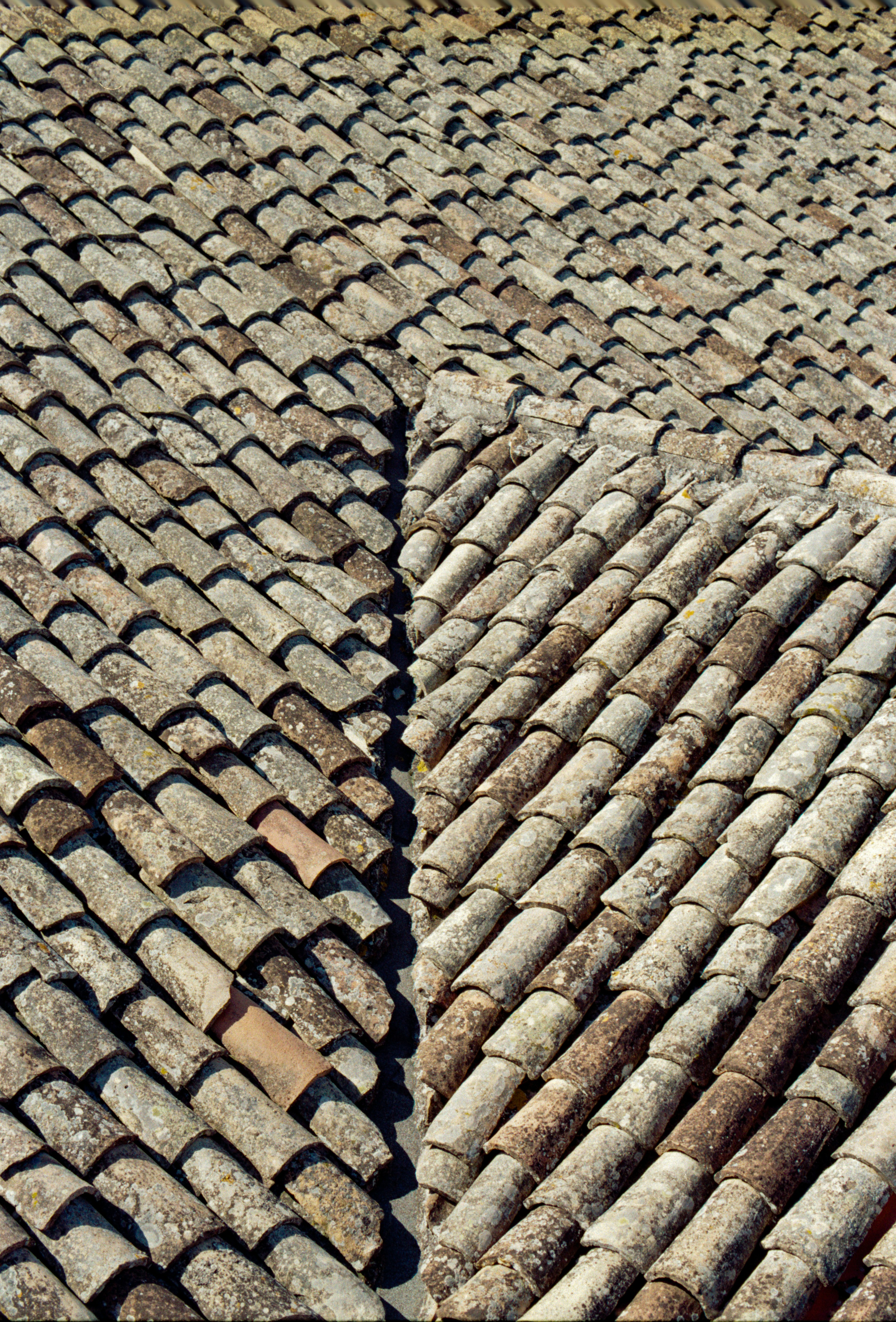 Tiled roof with intersecting ridges under sunlight