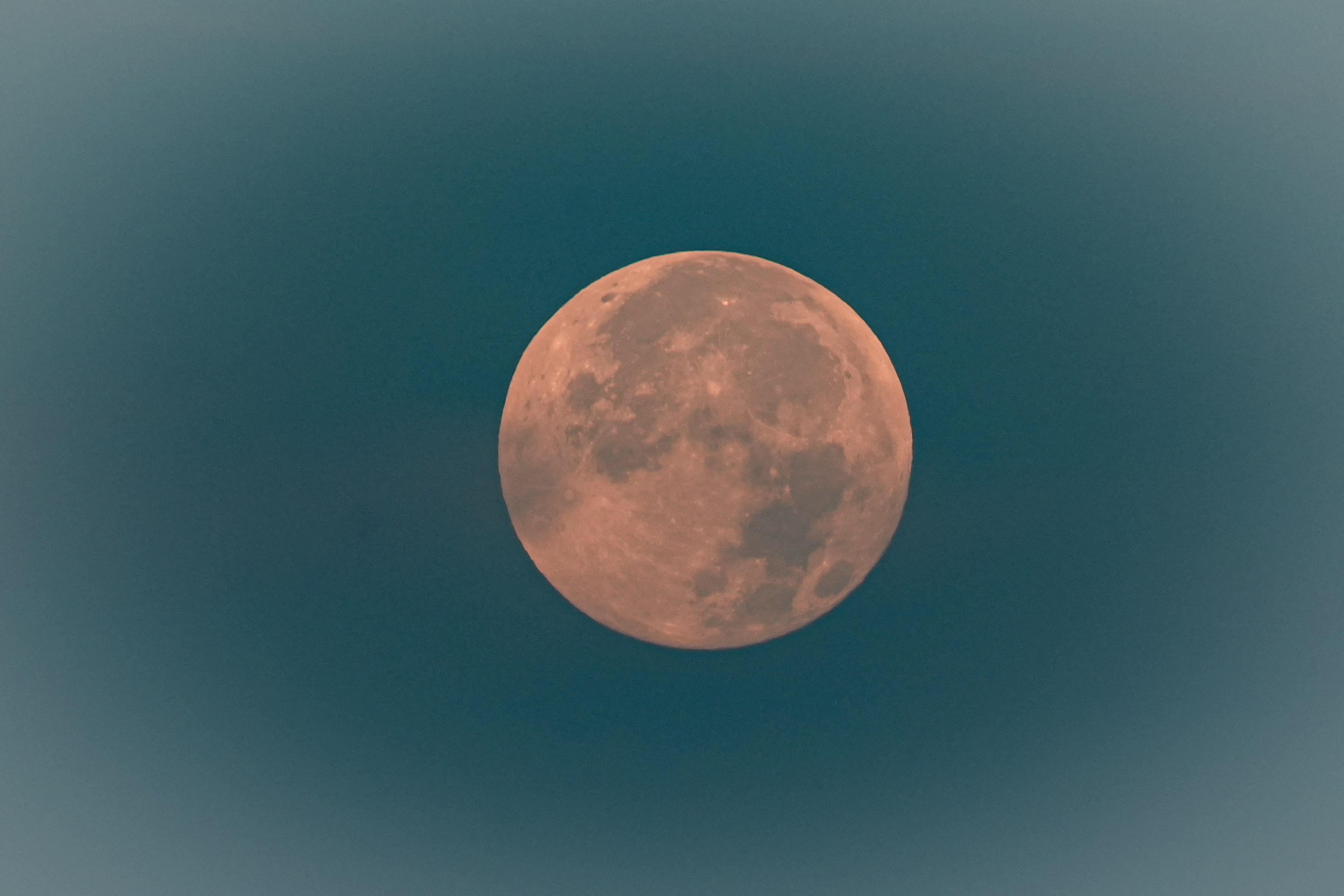 A large, reddish moon hangs in a dark sky.