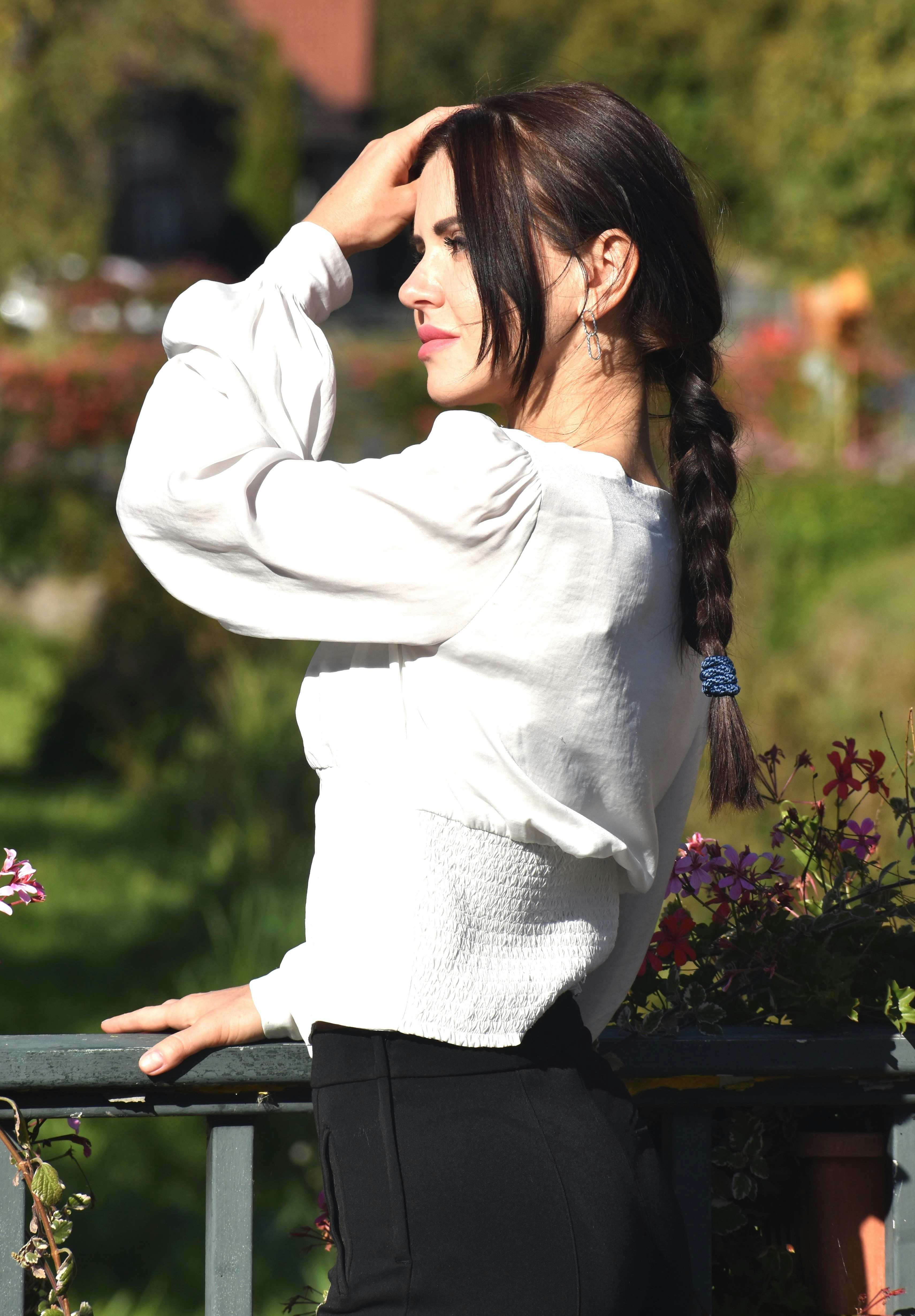Female Fashion | Woman with braided hair adjusts her hair outdoors.
