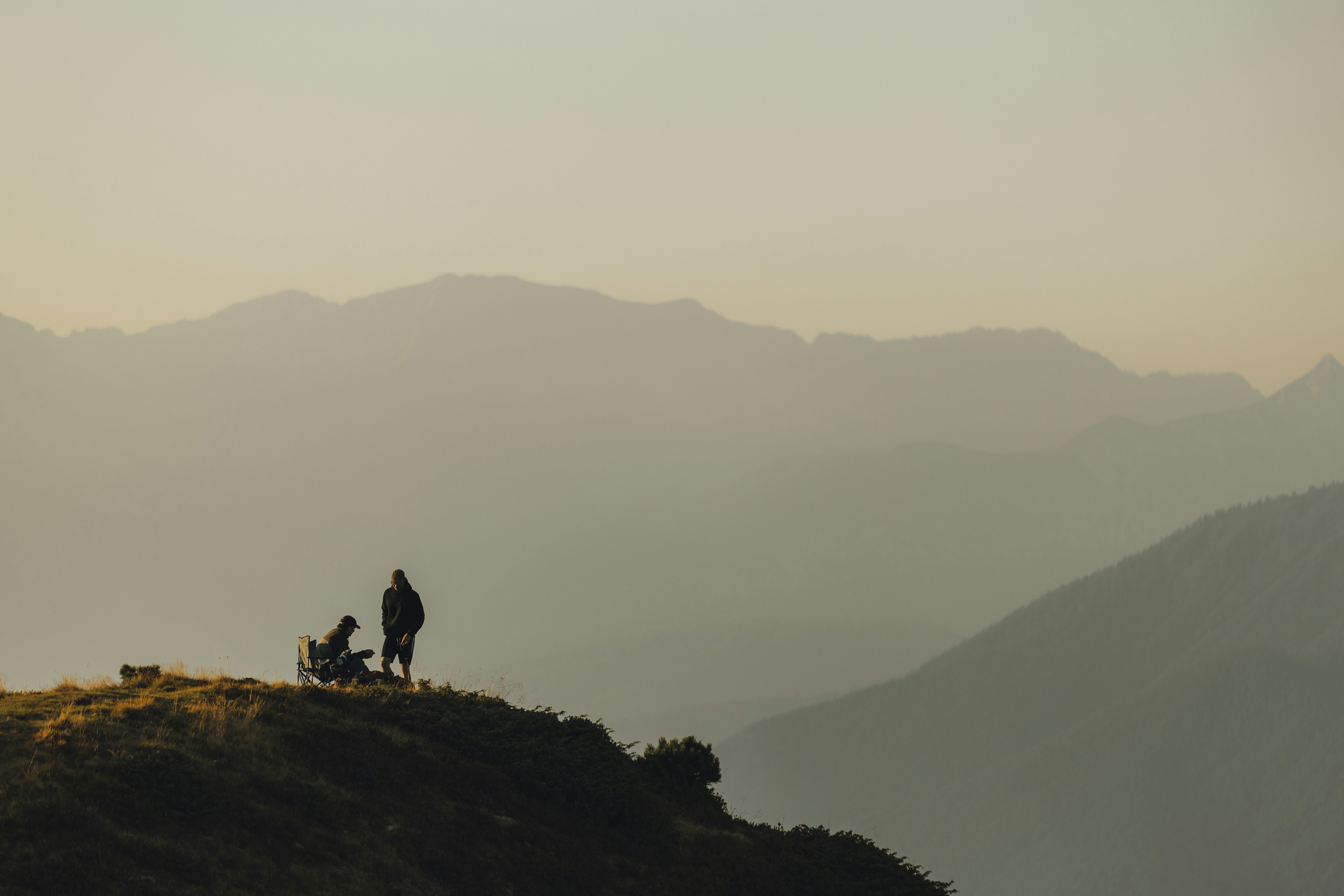 Silhouettes of people on a mountain ridge at sunset.