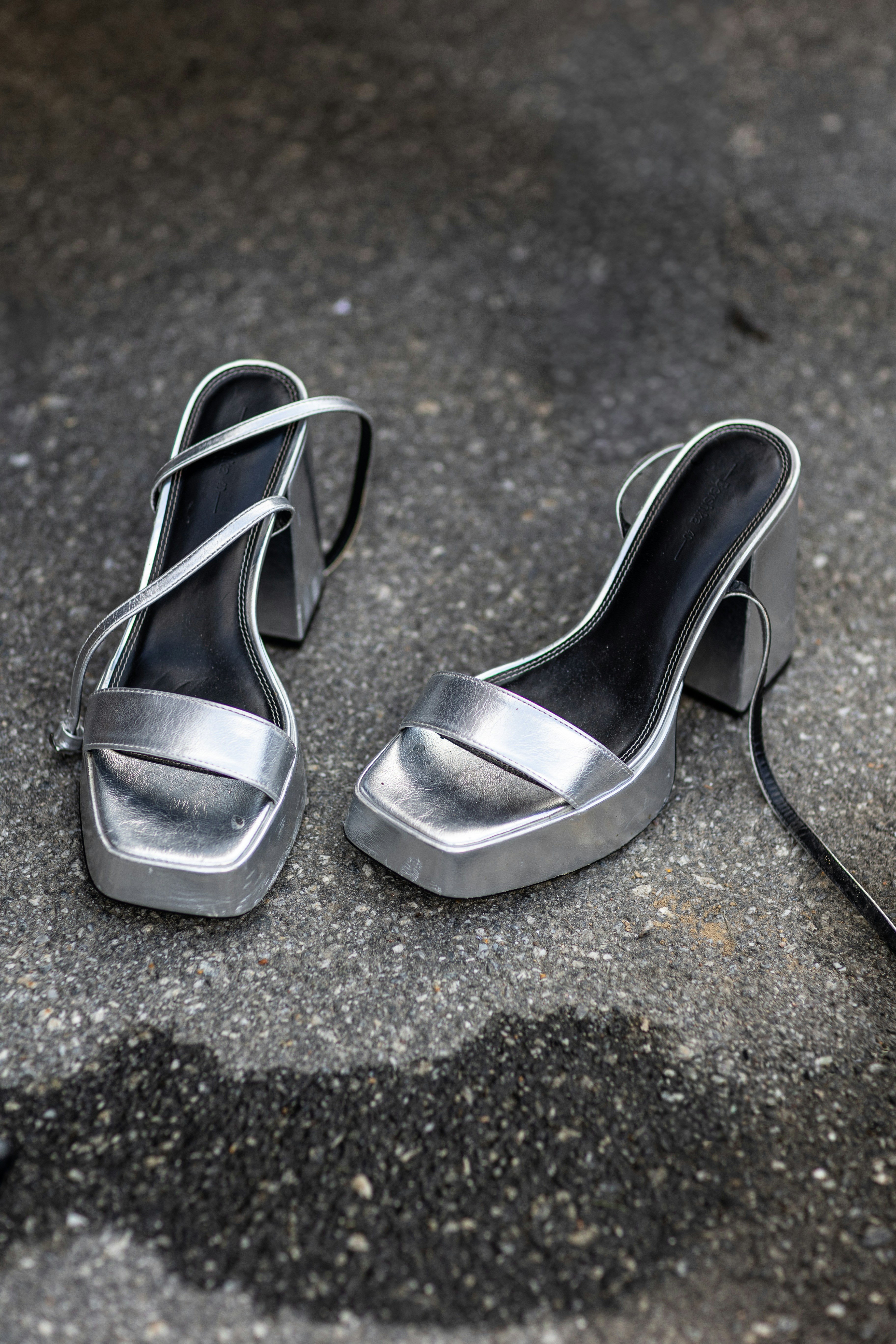 Silver platform heels resting on a wet surface.