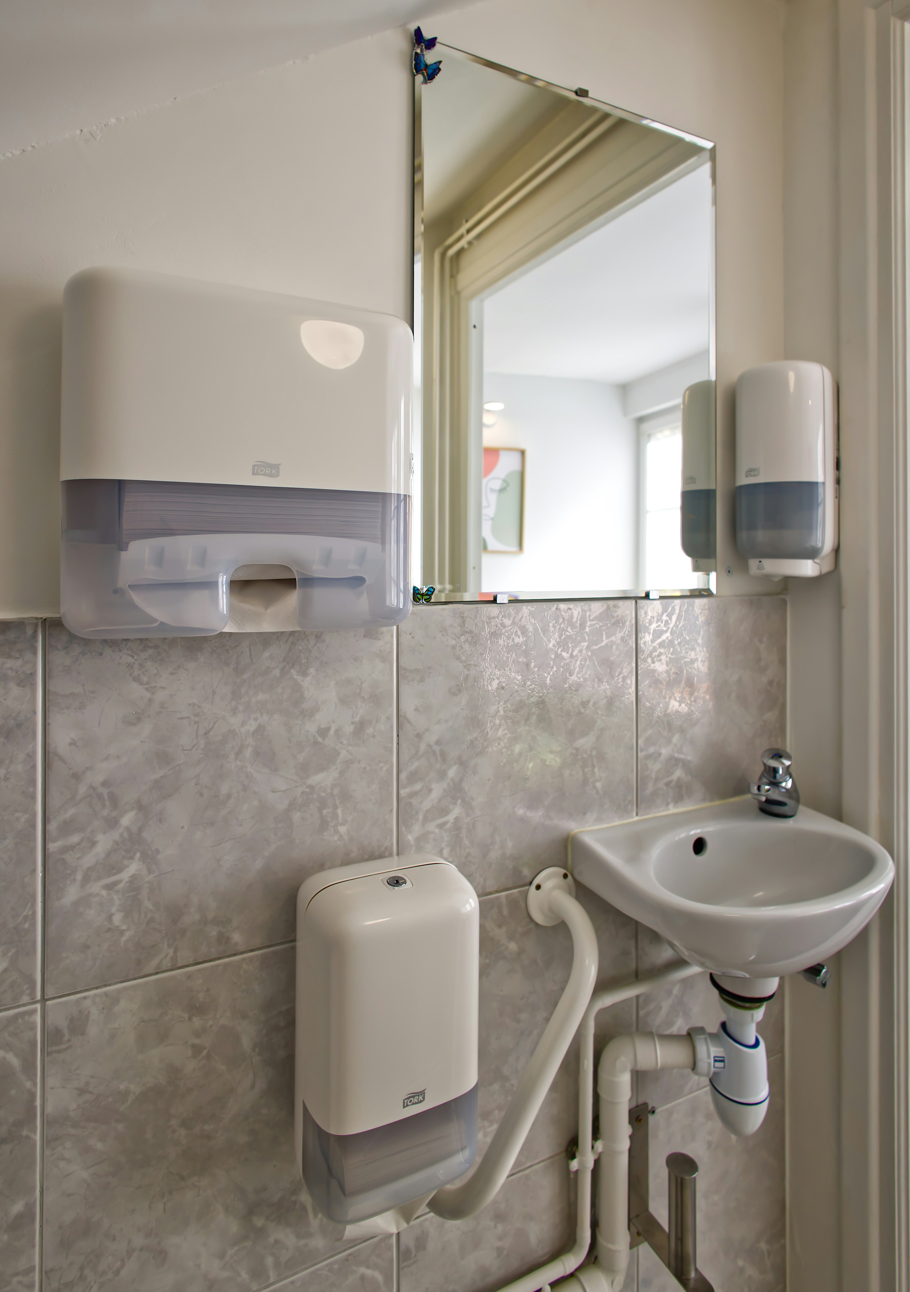 A small sink with soap and paper towel dispensers.