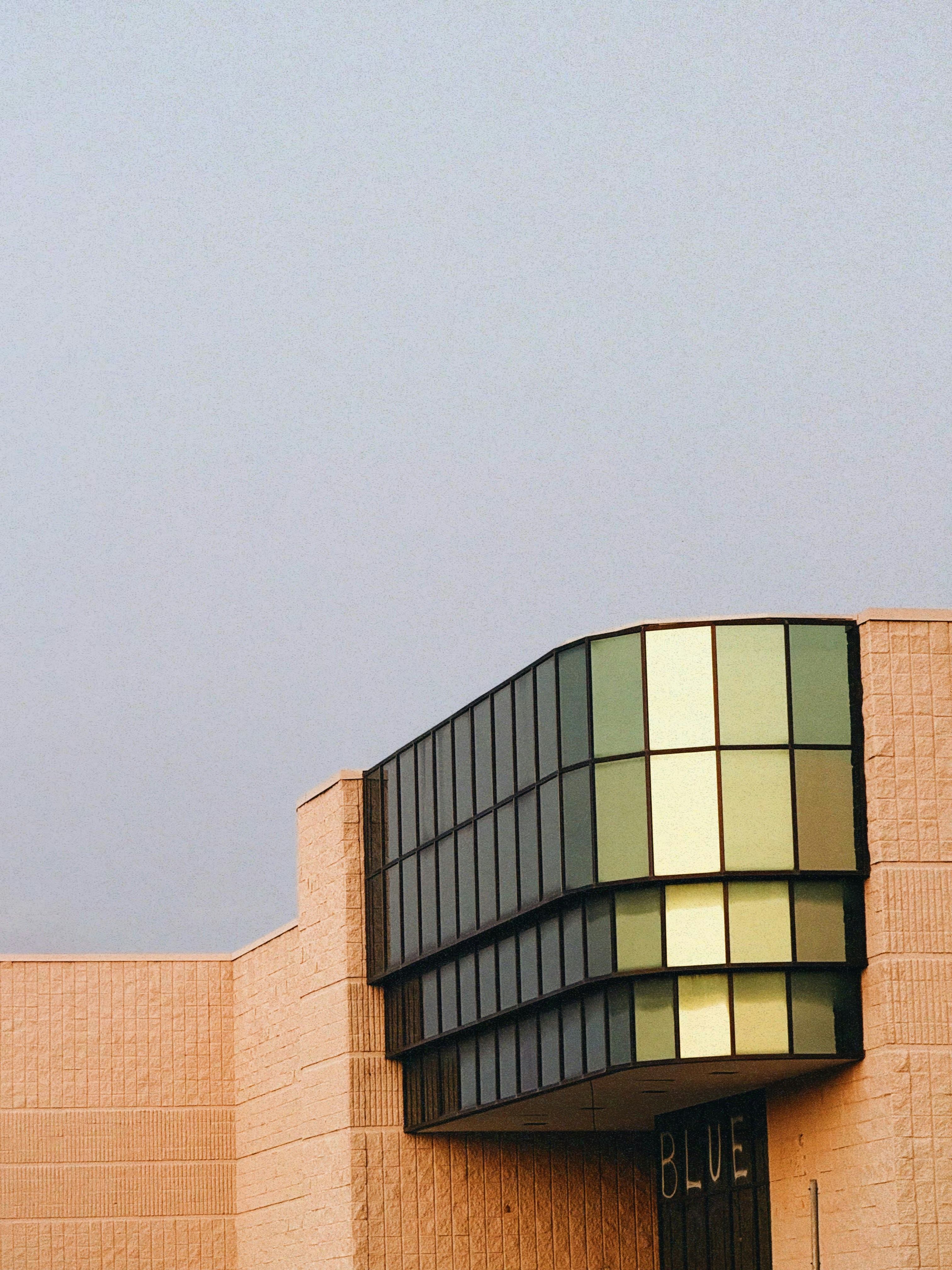 Curved glass overhang on the soft-brown brick facade