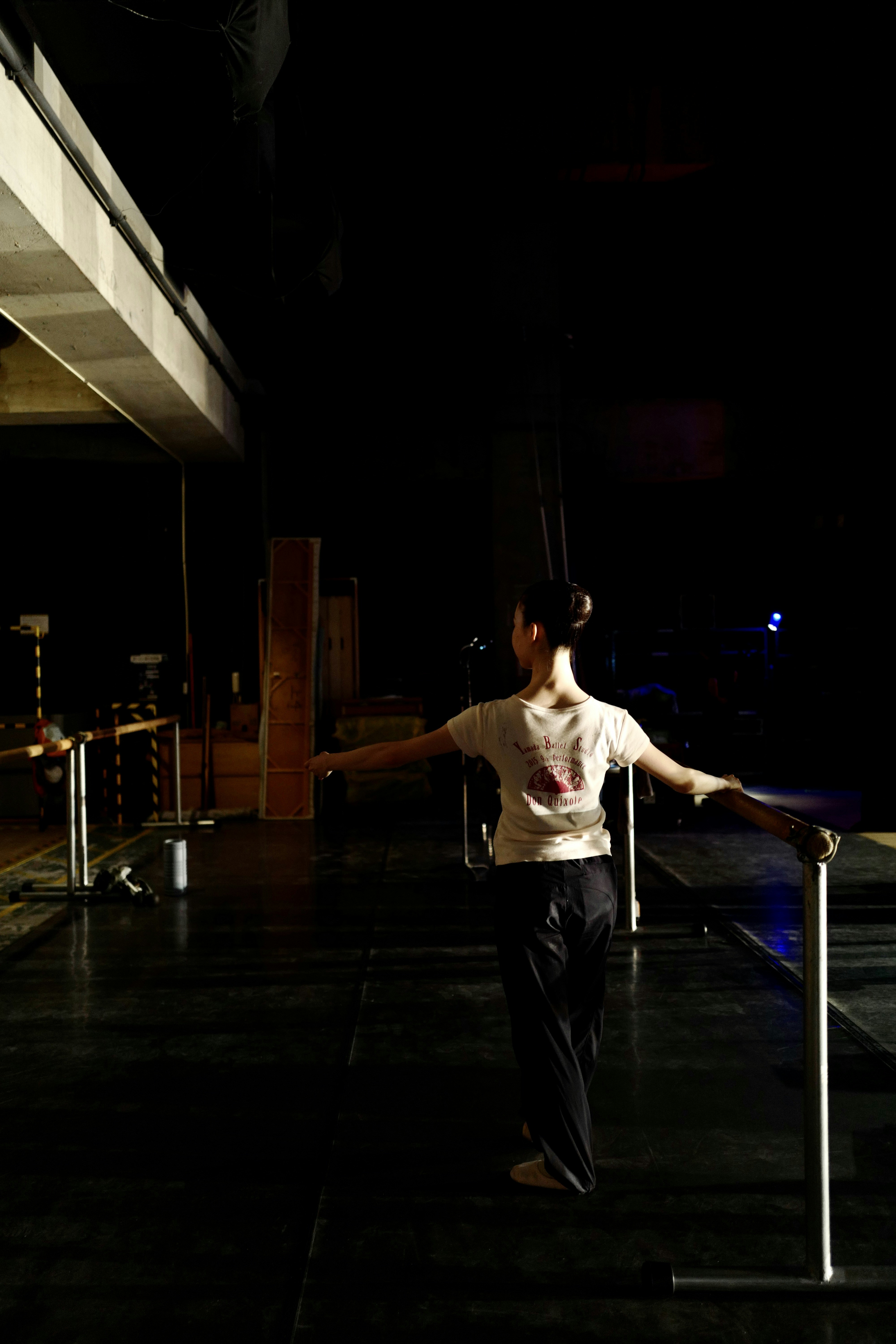 Ballet dancer practicing in a dimly lit studio, showcasing poise and focus against a backdrop of industrial elements.