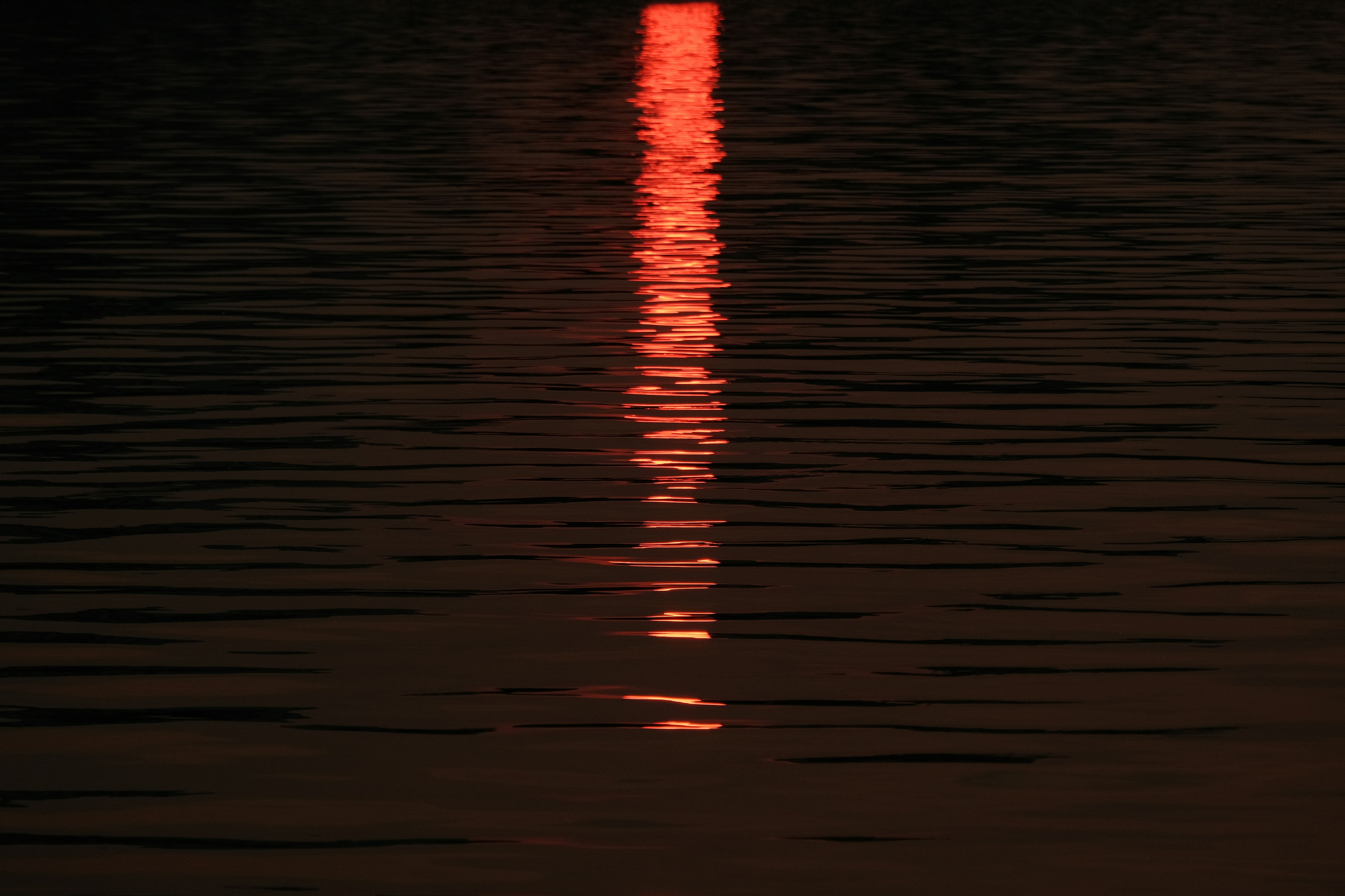 Red reflection on dark rippling water surface