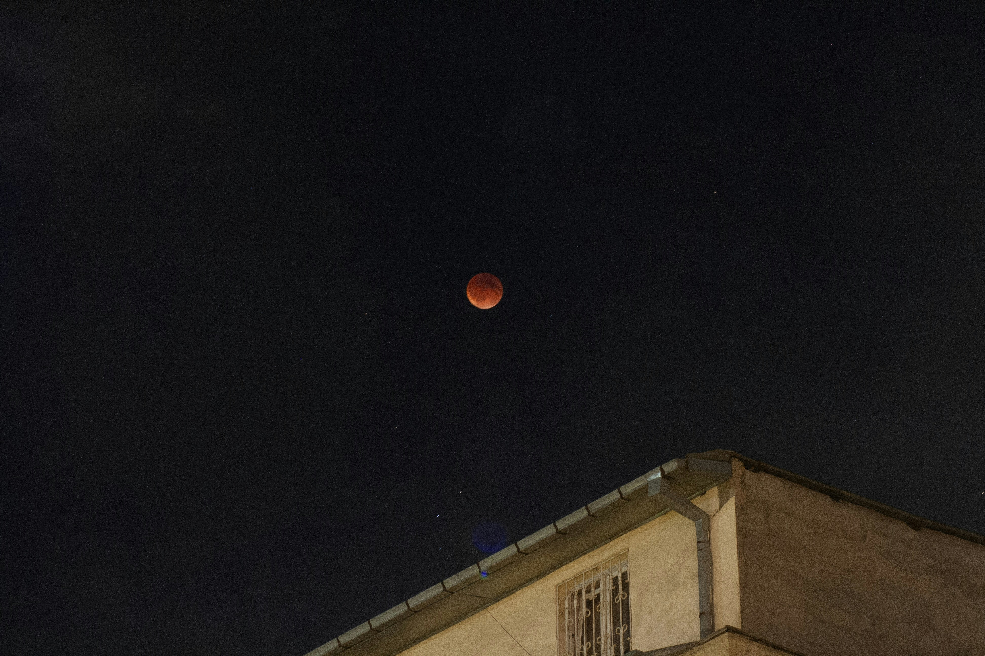 Red moon in the night sky above building