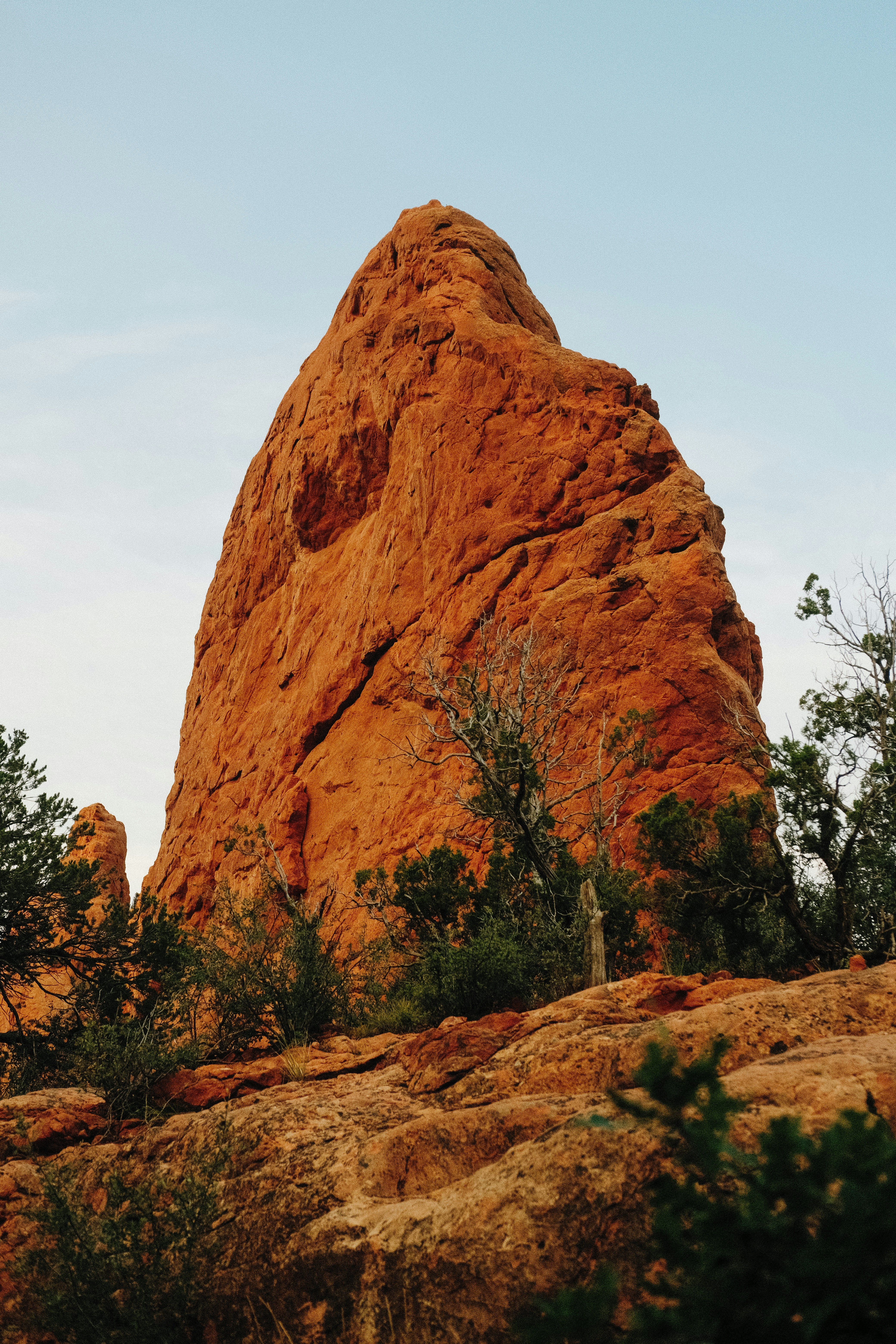 Tall orange rock formation with green bushes