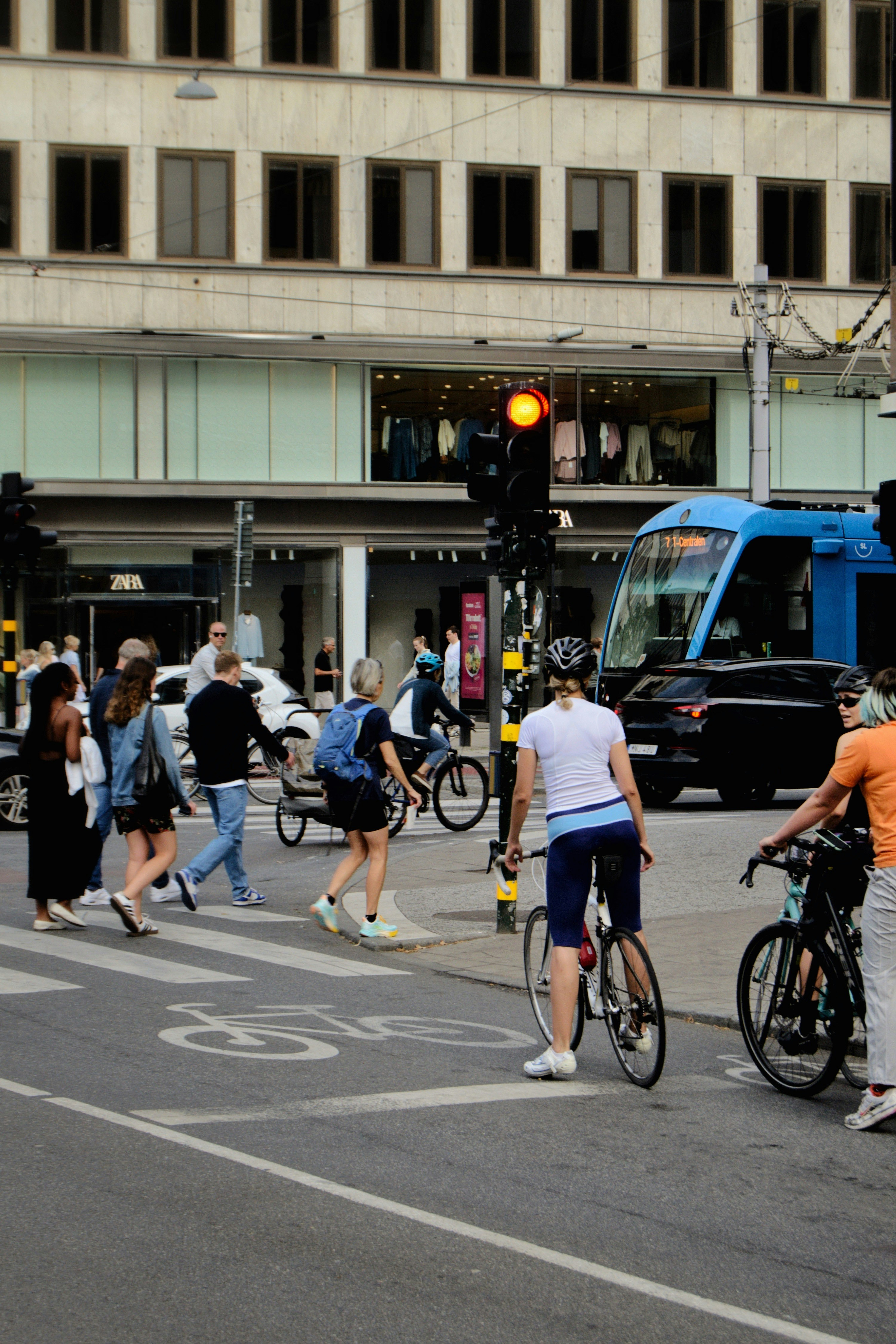 People crossing street with bicycles and tram.