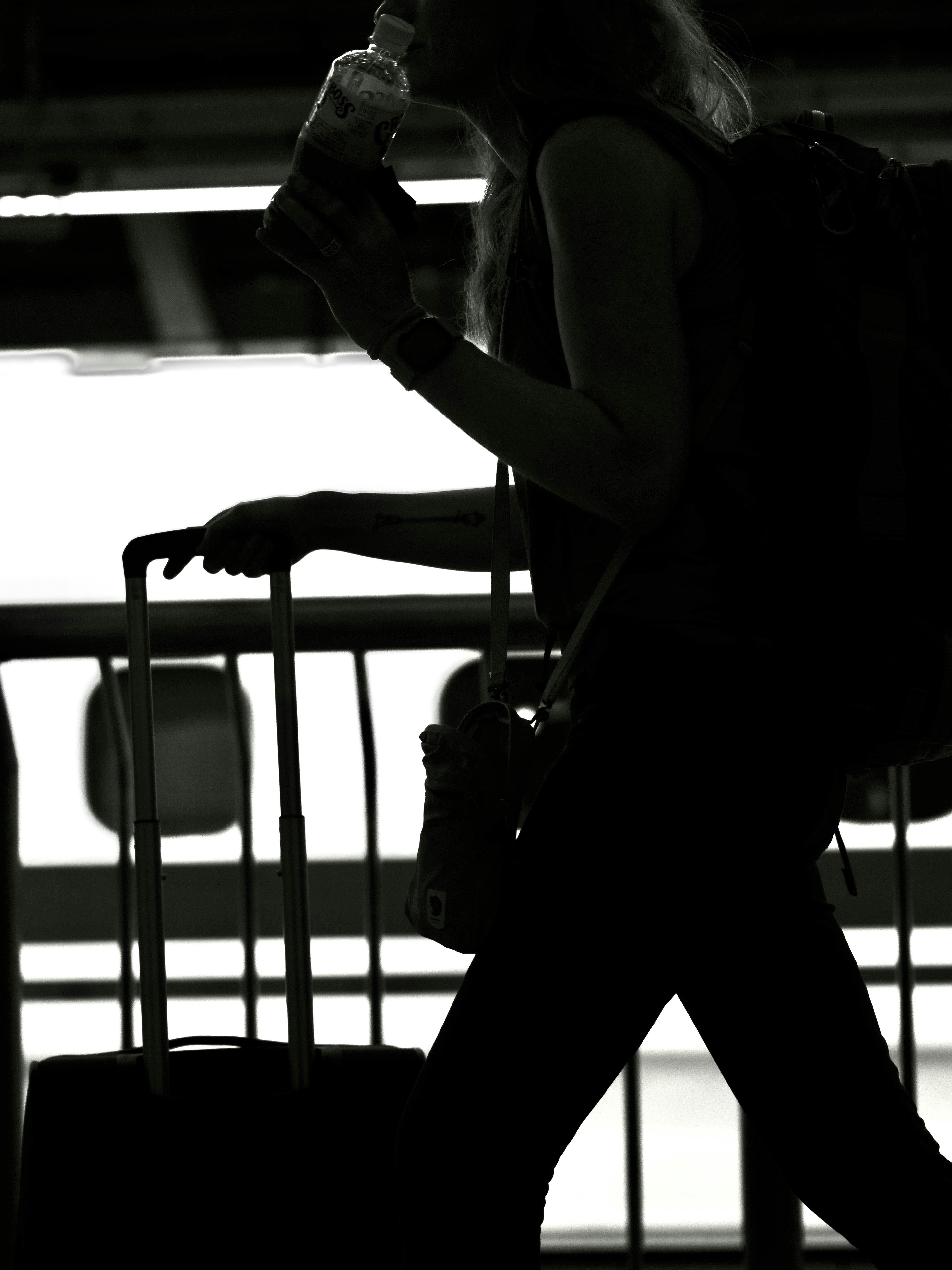 The silhouette of a traveller with a suitcase in a train station | Silhouette of a person with a suitcase and backpack.