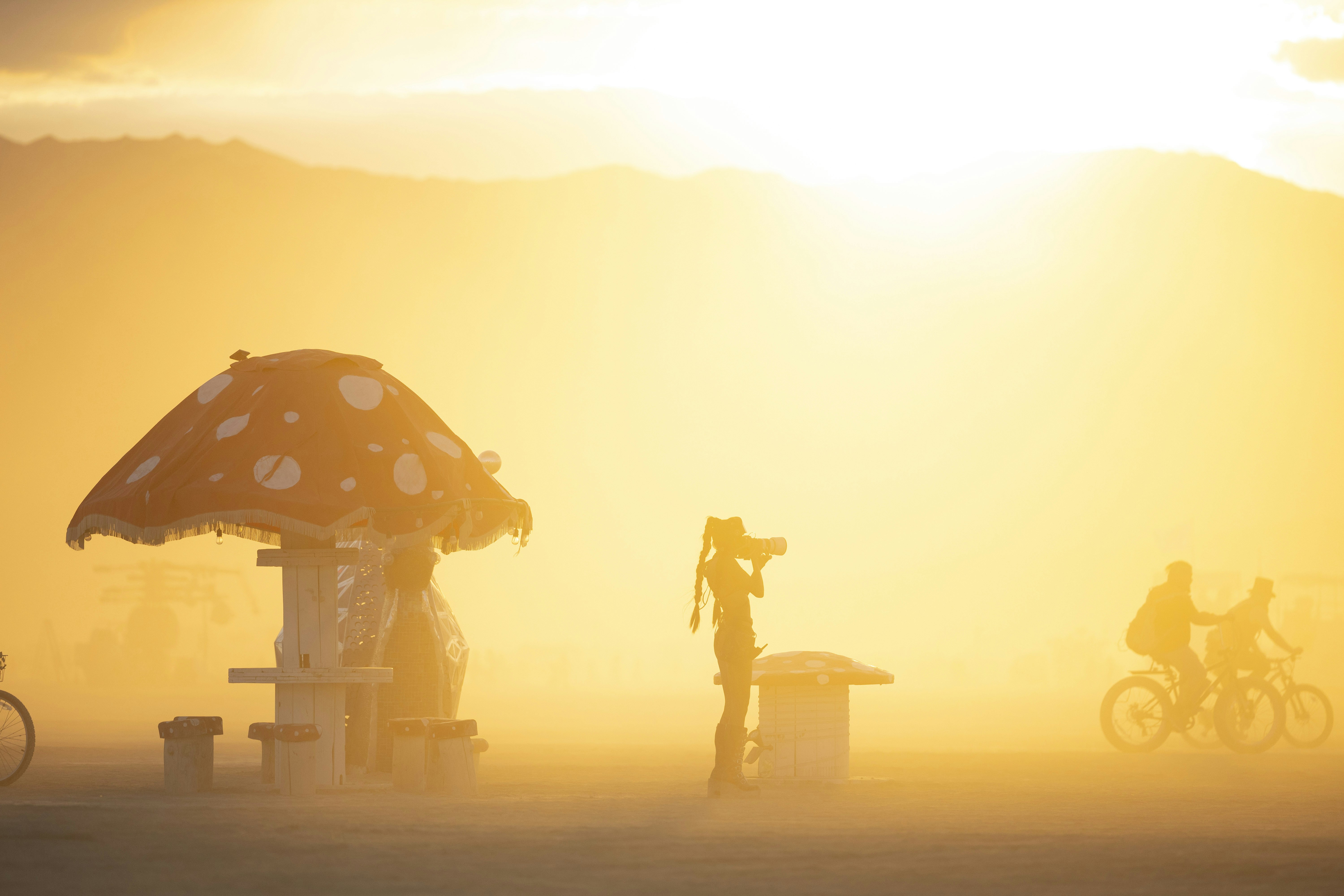 Mushroom Pavilion at Golden Hour: A Beachfront Silhouette with a Photographer