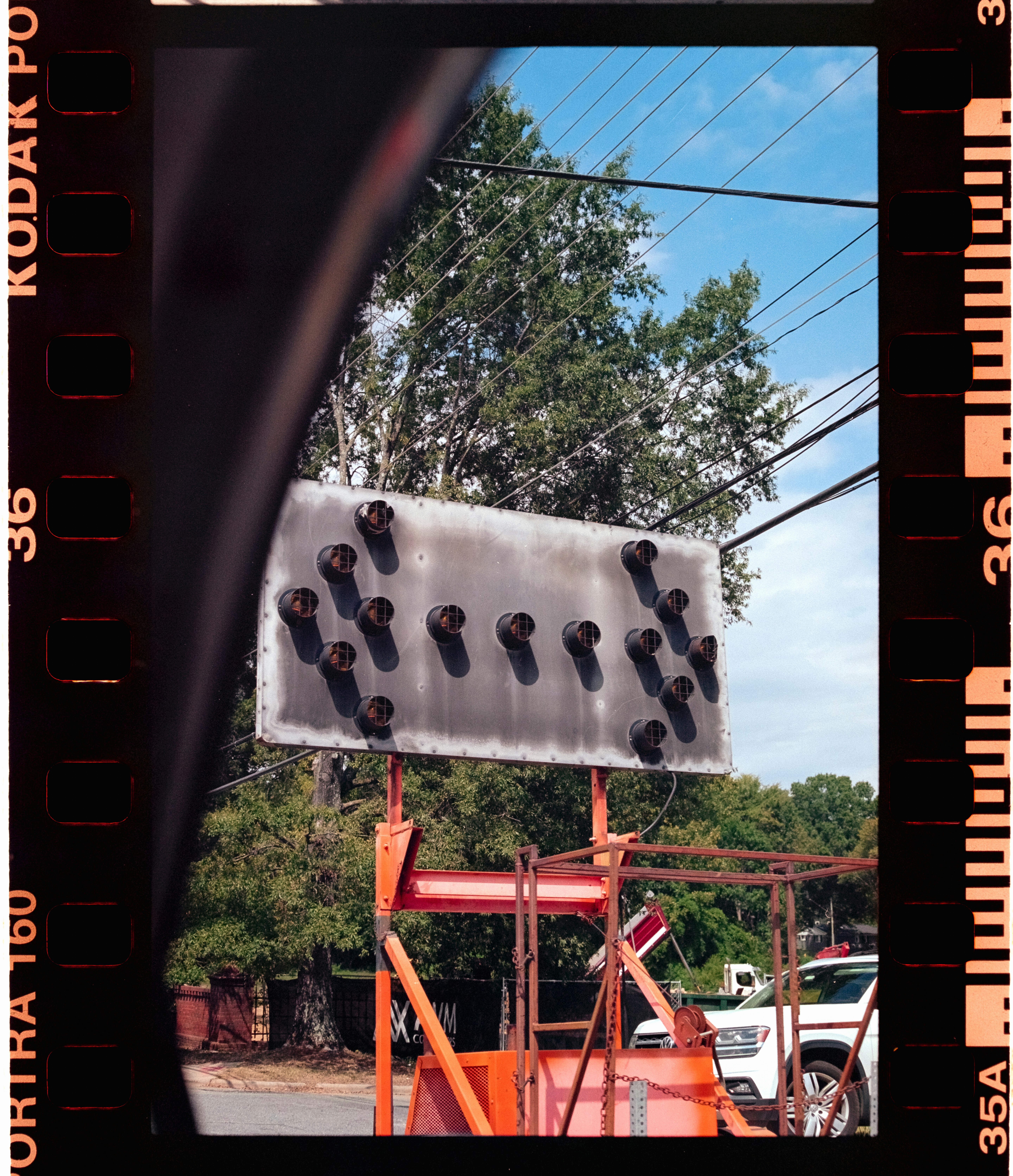 Perforated Metal Panel on Orange Scaffold Under a Sunny Sky, Framed by Film Borders